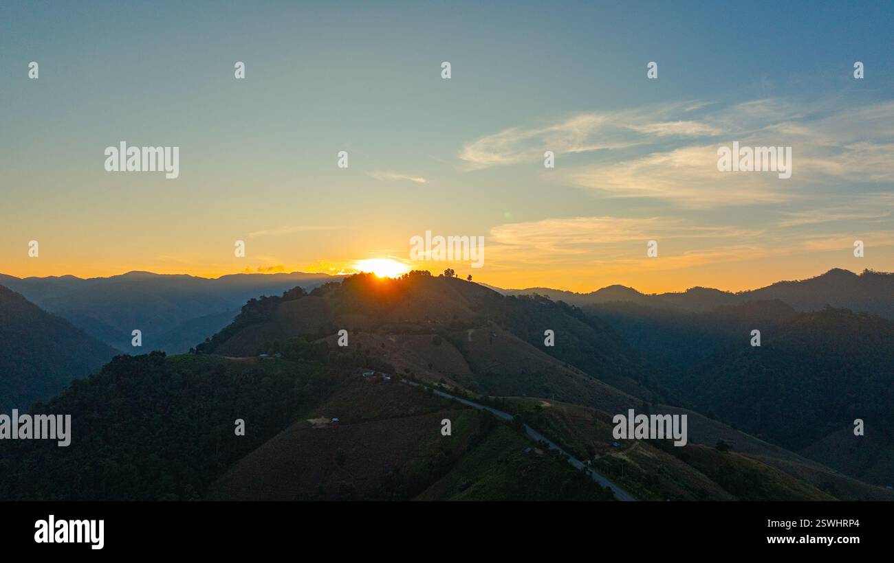 Aerial view of serene sunset casts a golden glow over rolling hills and ...