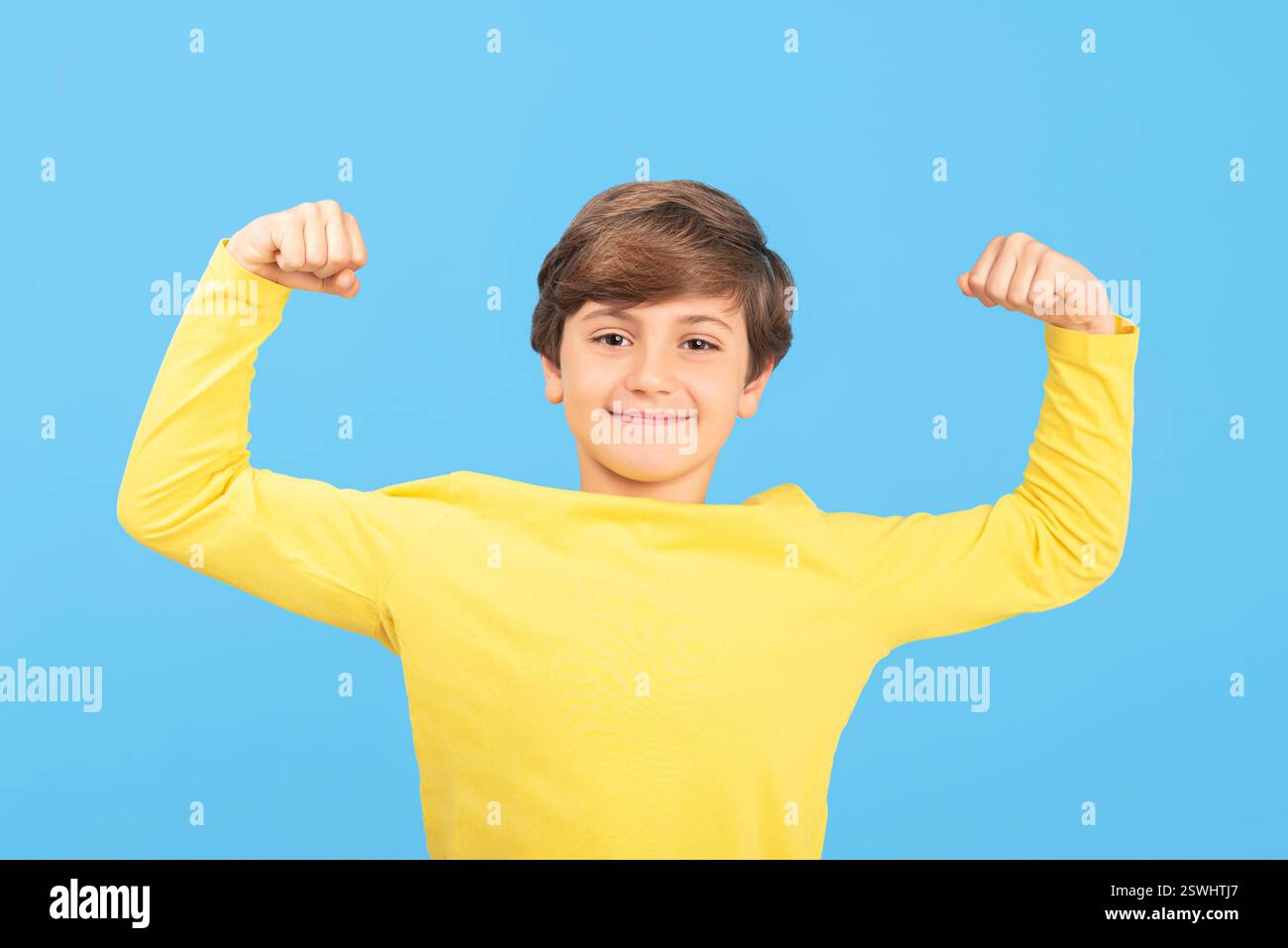 Boy raising arms with clenched fists, showing biceps, smiling face ...