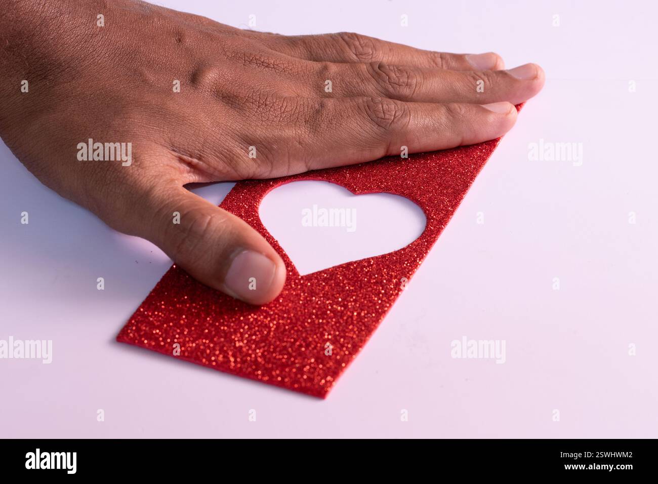 Red colored heart template taken out from the red glittering sheet with ...