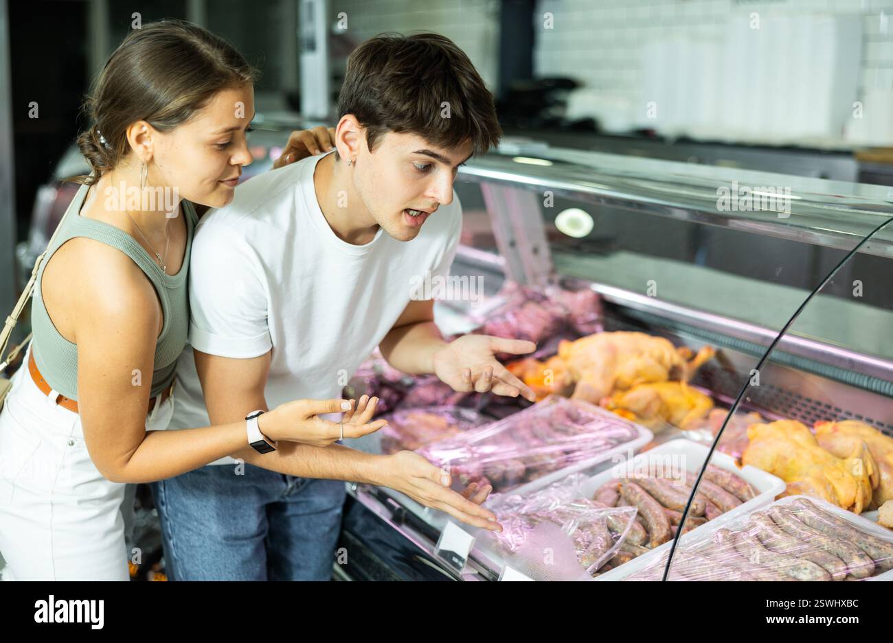 Spouse near butcher shop window inspects goods and choose sausages for ...