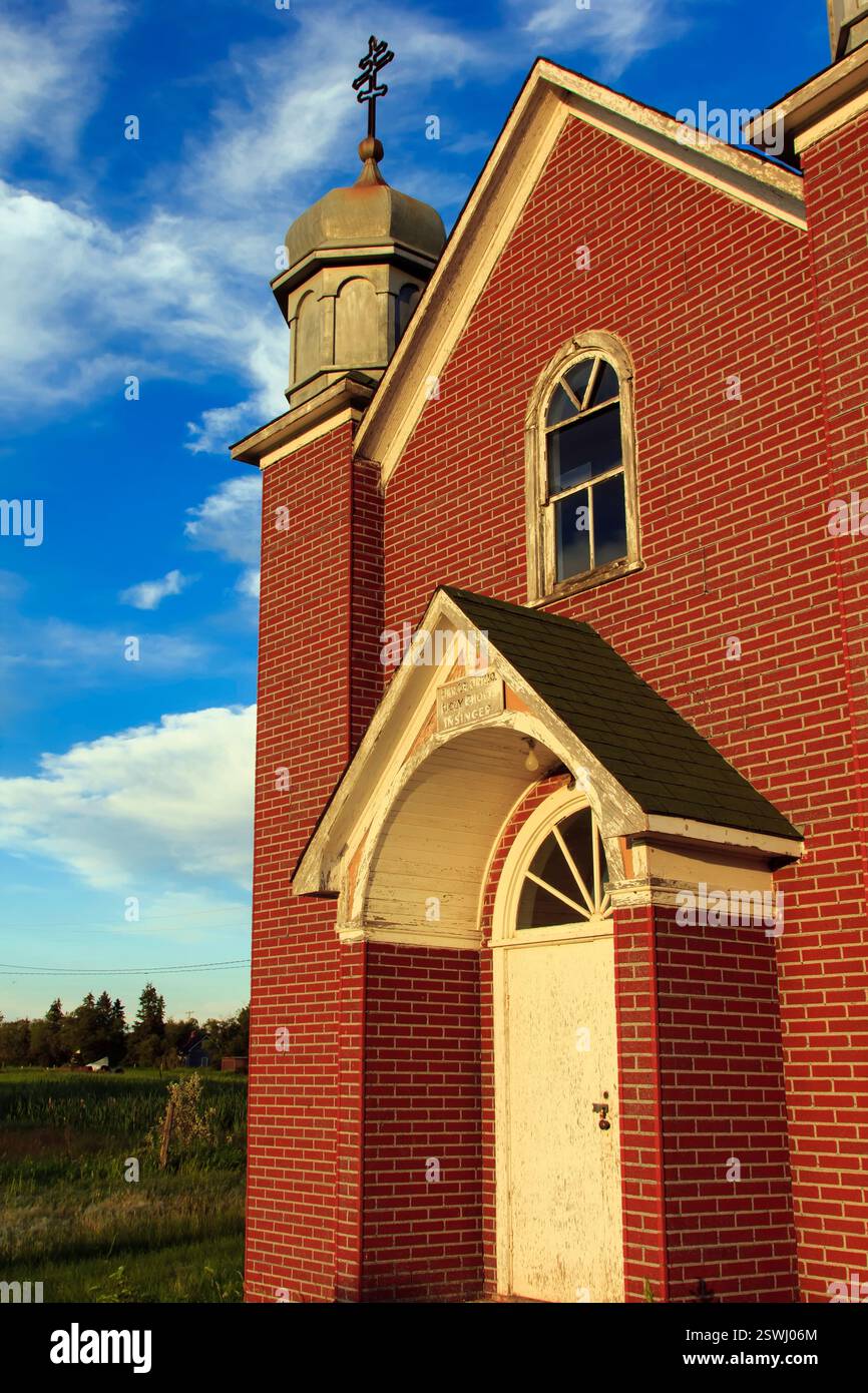 Brick building with a steeple and a cross on top. The building is old ...