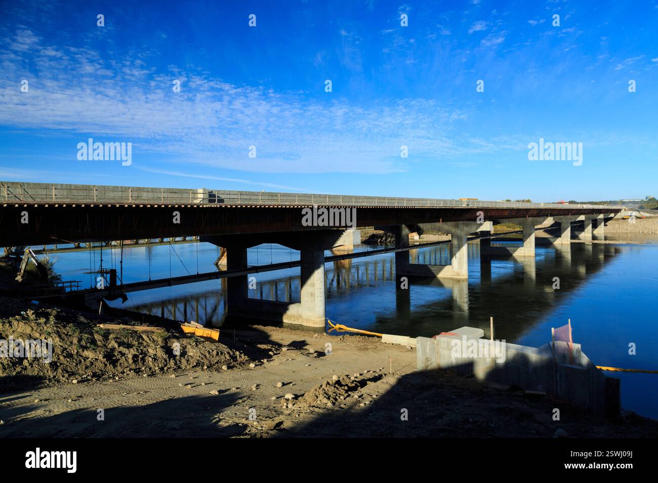 Bridge is being built over a river. The bridge is made of concrete and ...