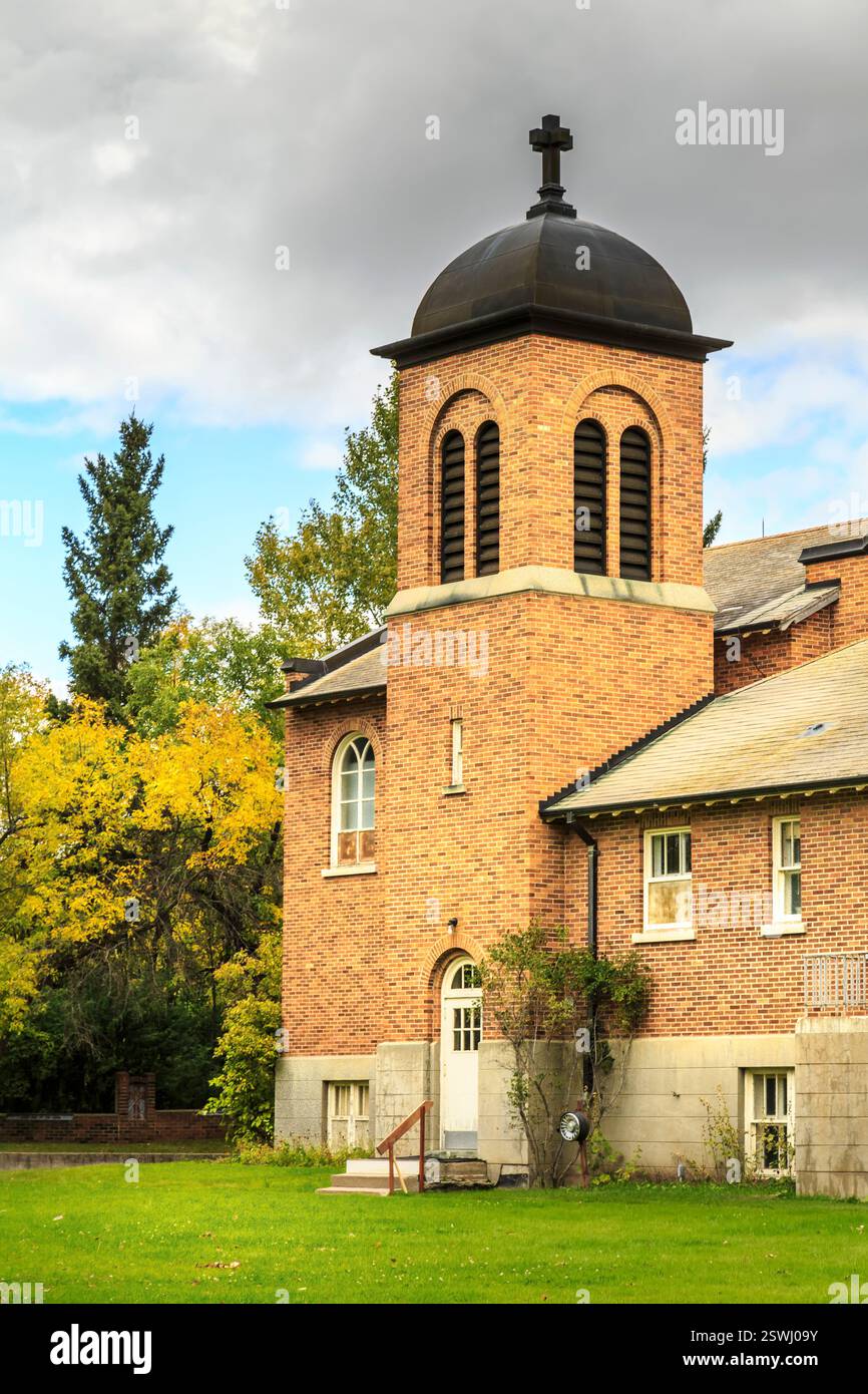 Brick building with a tall steeple and a cross on top. The building is ...