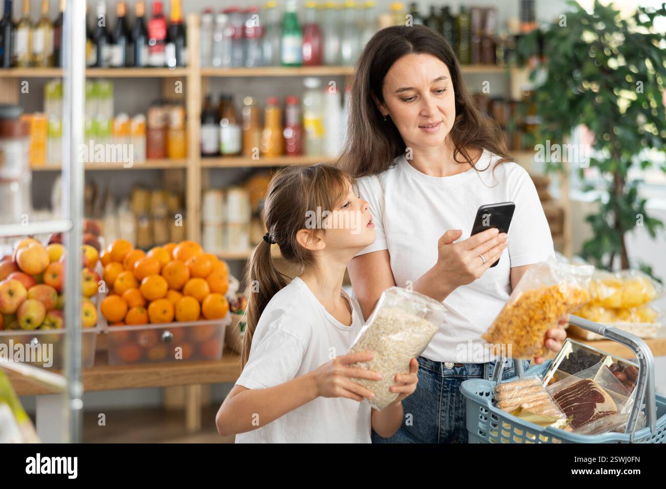 Mother and daughter checks expiration date of cornflakes and oat flakes ...