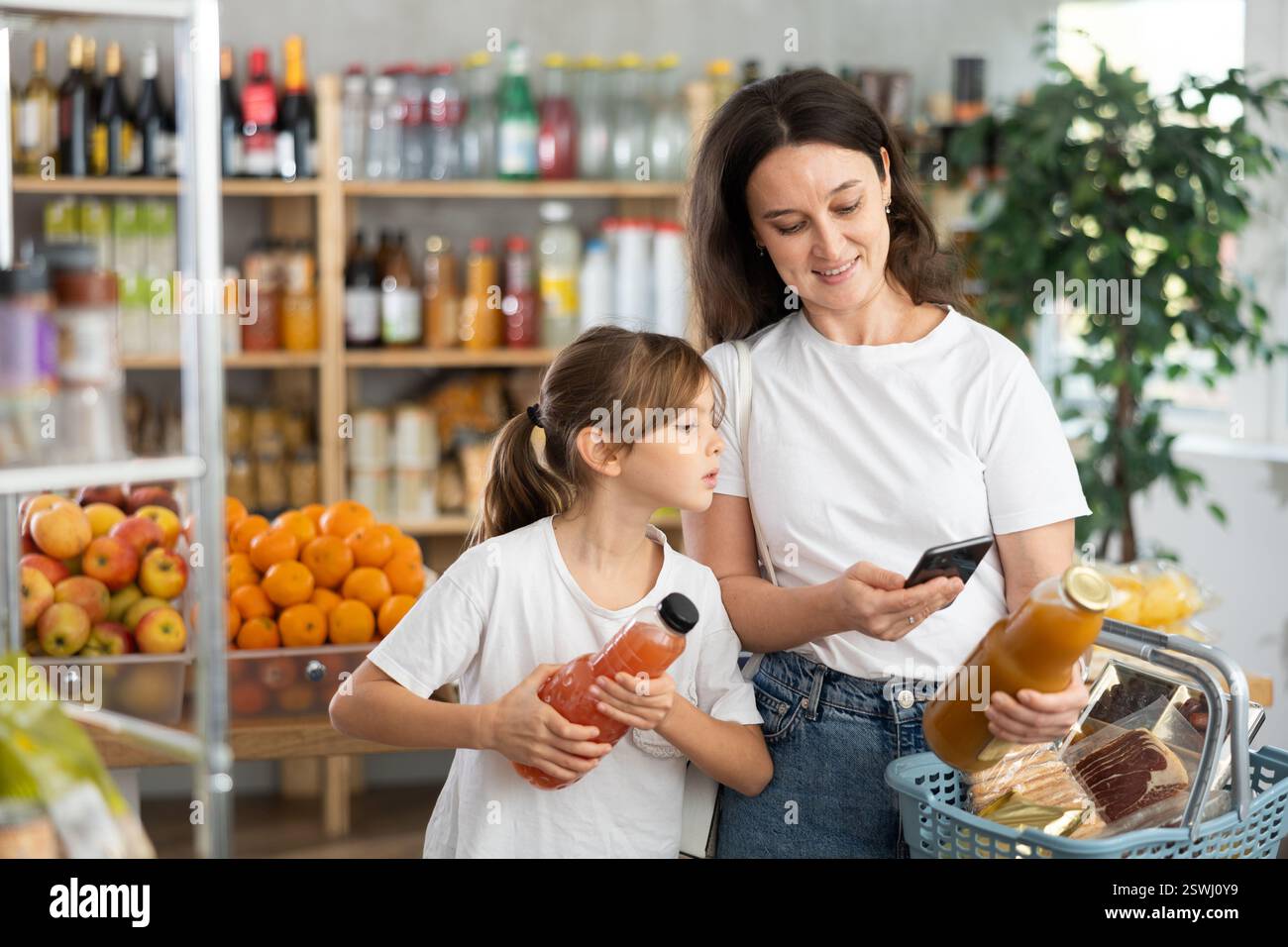 Mother and daughter choose bottles of juice and scan QR code with ...
