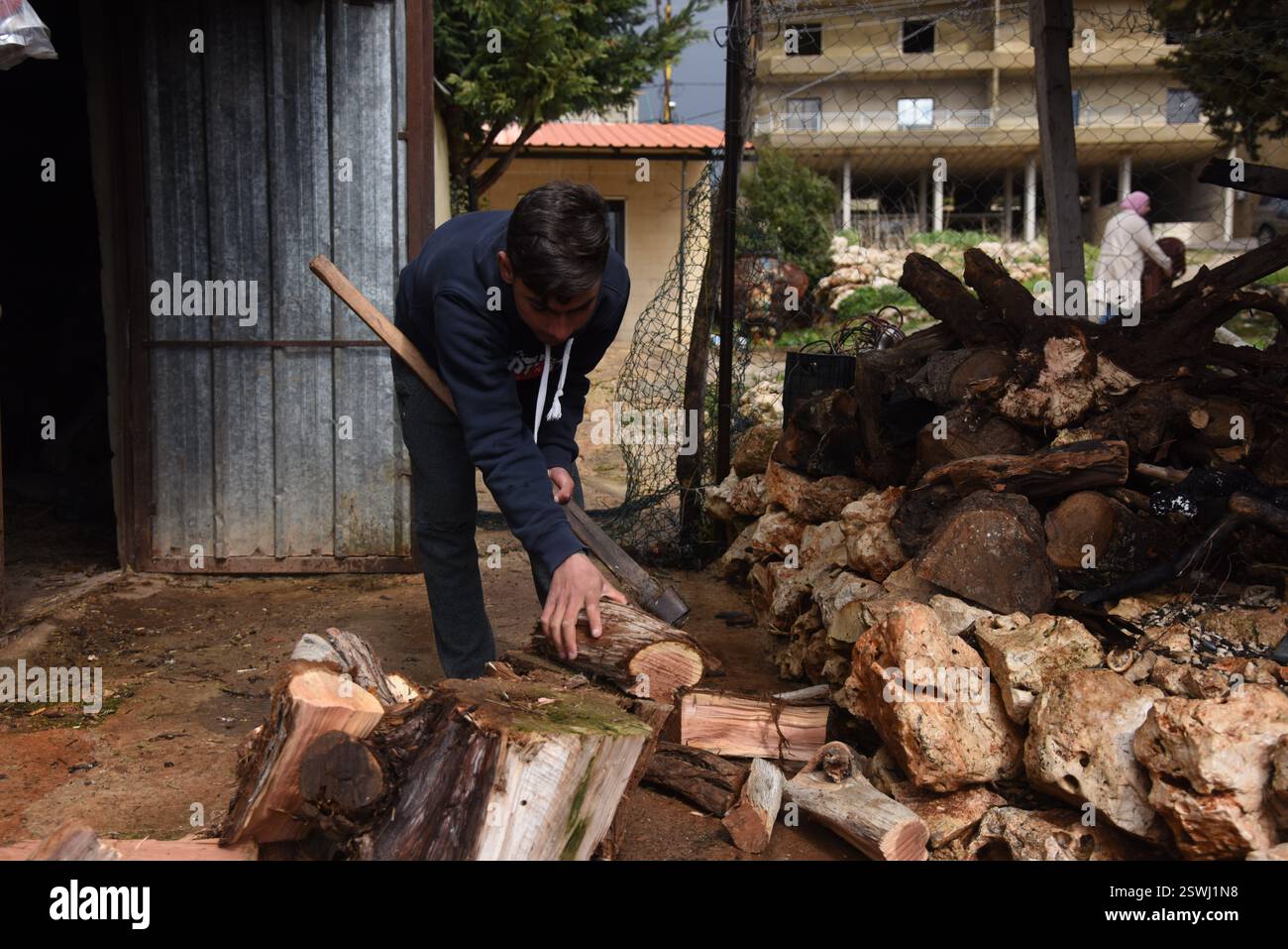 Akkar, Lebanon. 19th Feb, 2025. A young man cuts firewood in ...