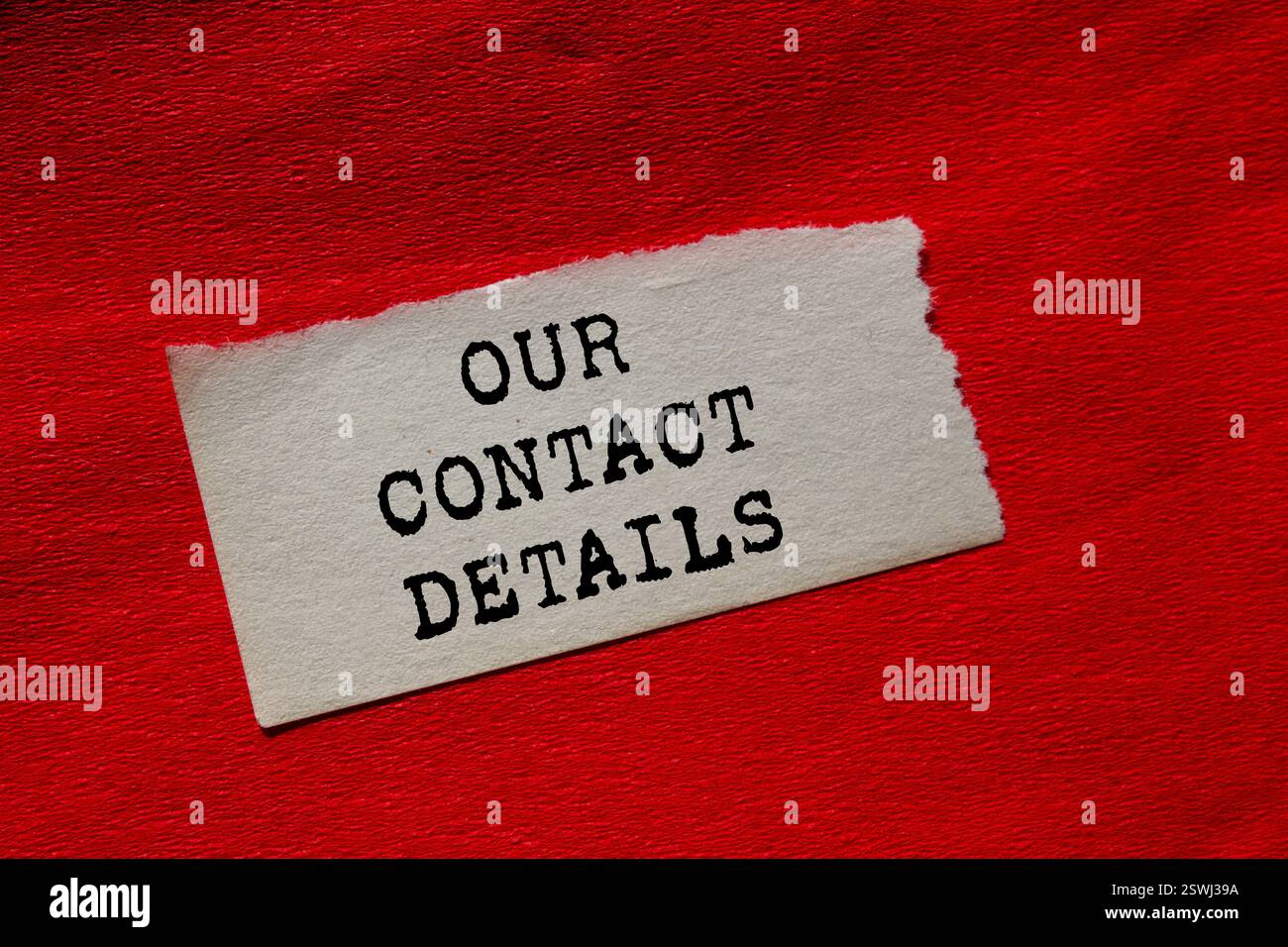 Our contact details message written on ripped torn paper piece on red ...