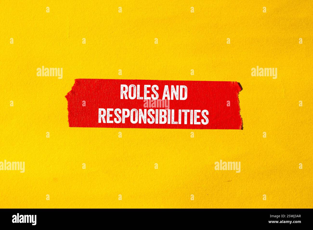 Roles and responsibilities message written on ripped torn red paper tape on yellow background ...