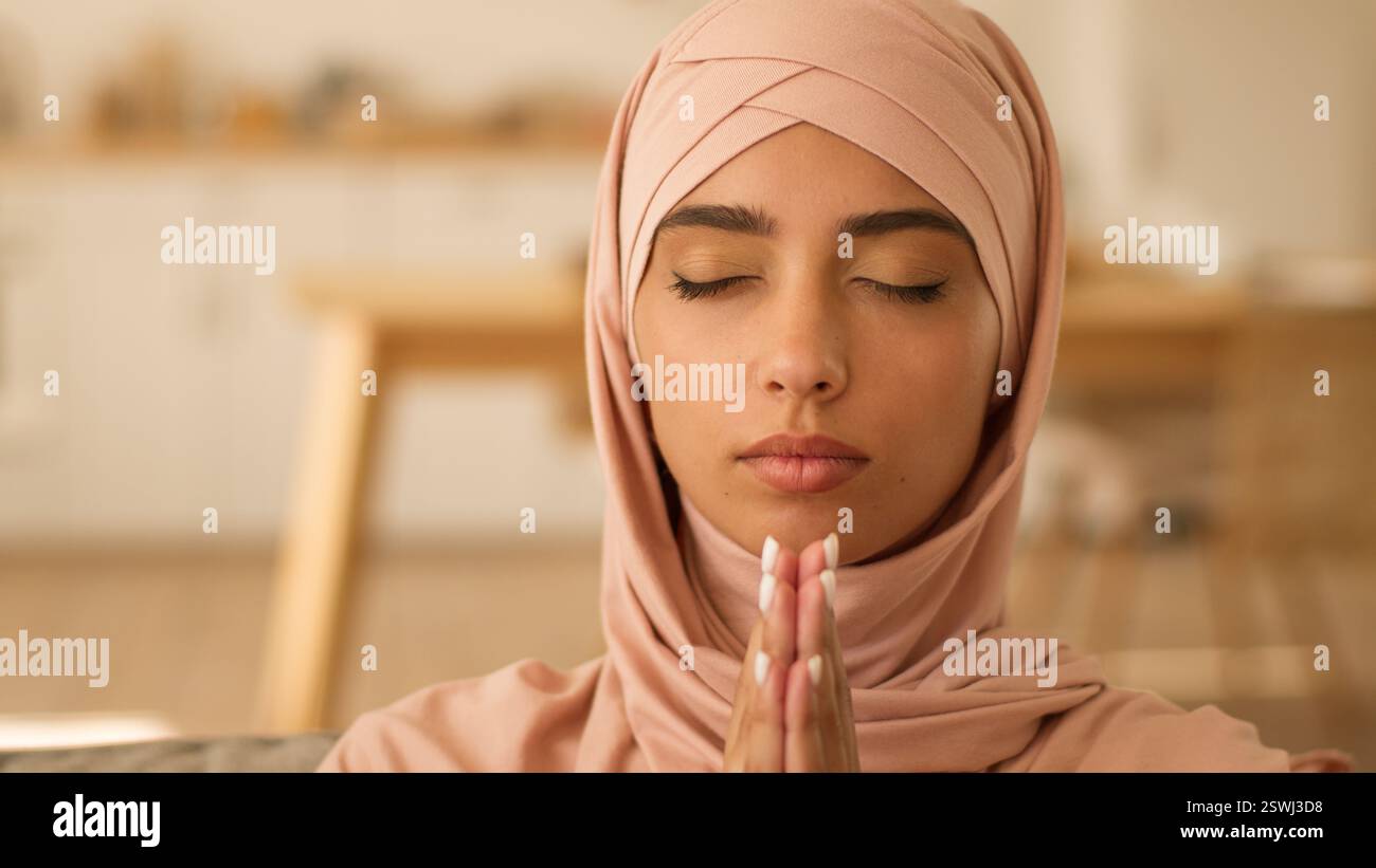 Woman in hijab close eyes hope praying God folded palms in pray religion culture prayer Arabian ...