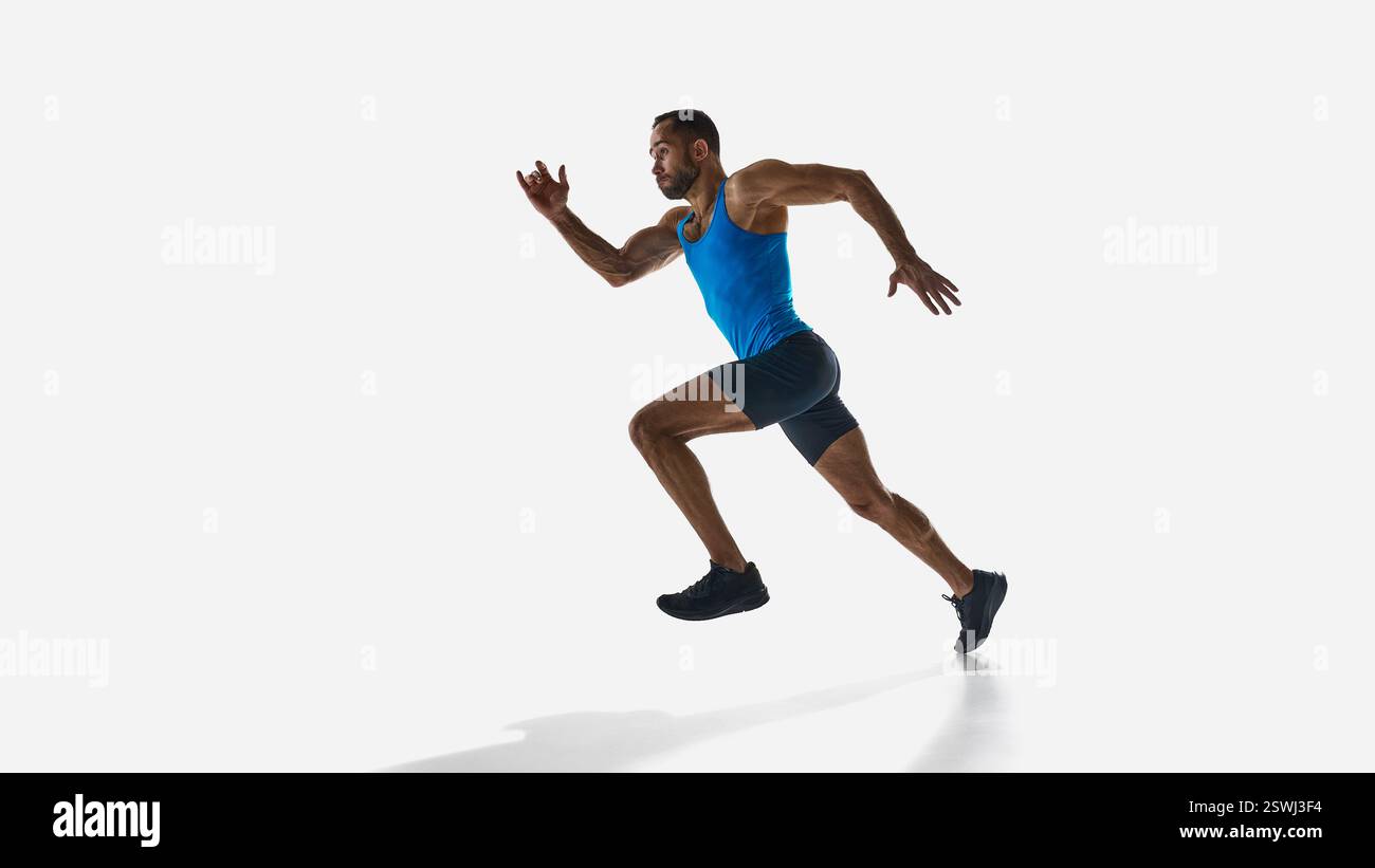 Muscular determined man, runner in blue jersey and shorts in motion ...
