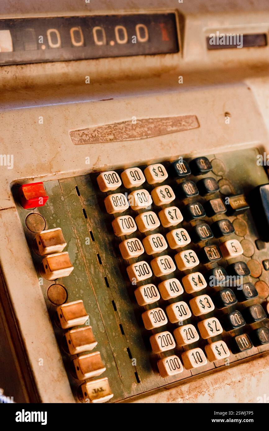 An old fashioned cash register with a red button on the top left. The ...