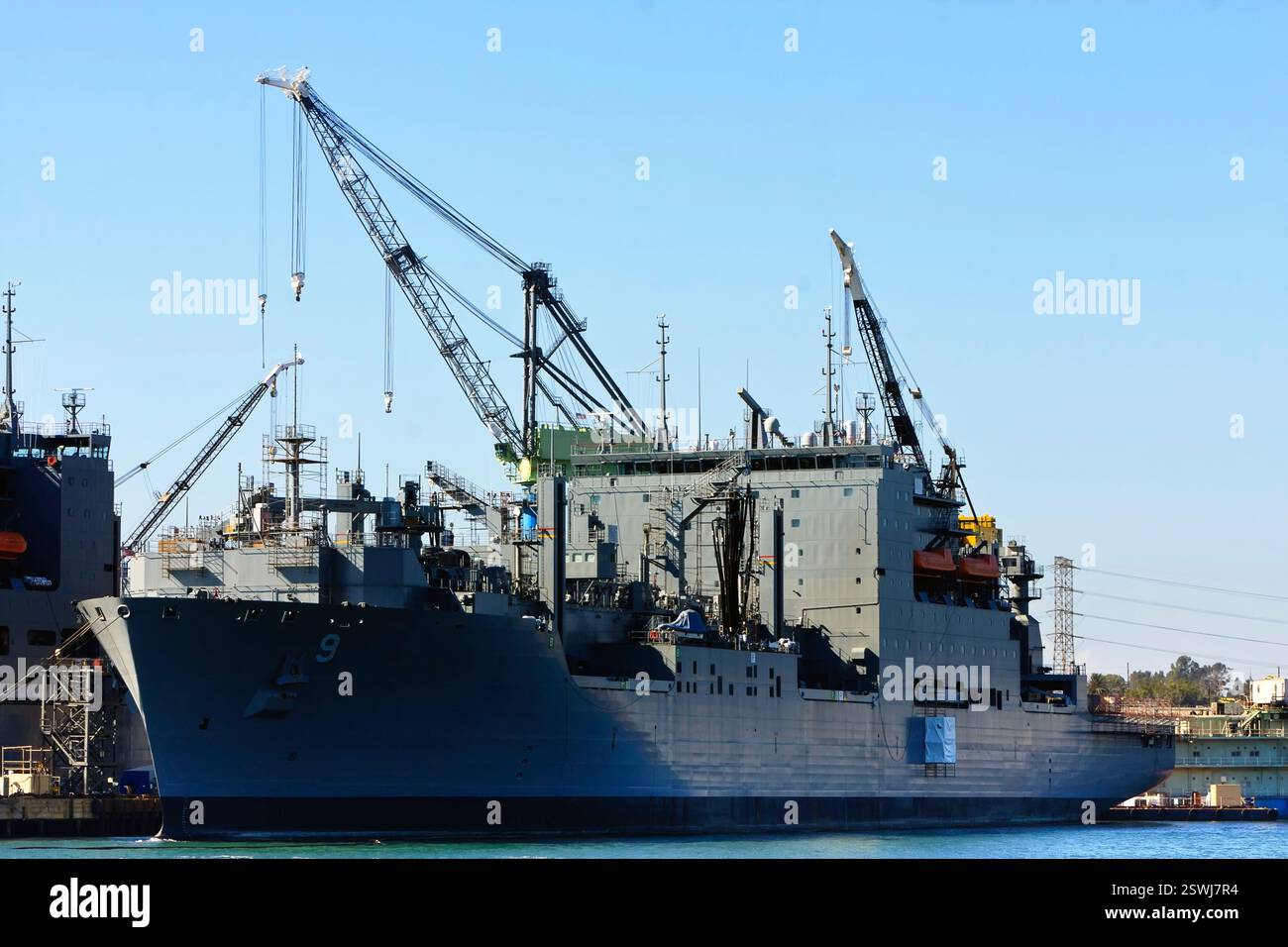 Large ship with a crane on it is docked at a harbor. The ship is ...