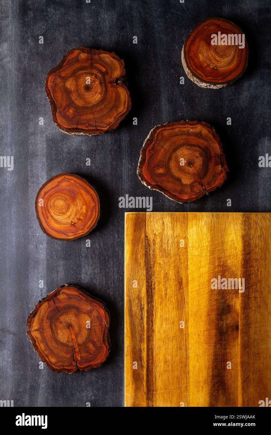 Wood log tree slices and cutting board on black chalkboard. Flat lay ...