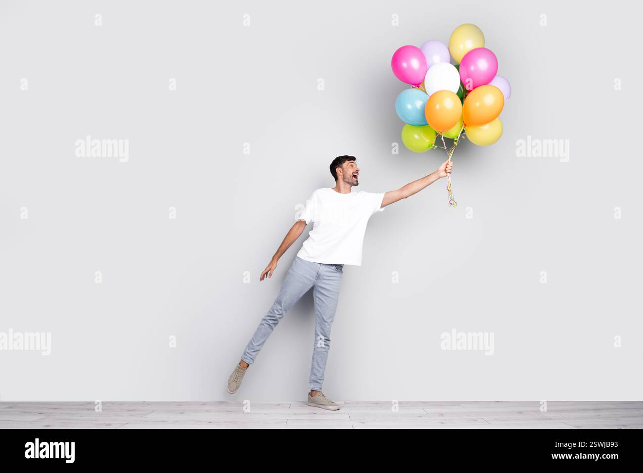 Smiling Young Man in Casual Style Holding Bright Balloons Levitating by ...