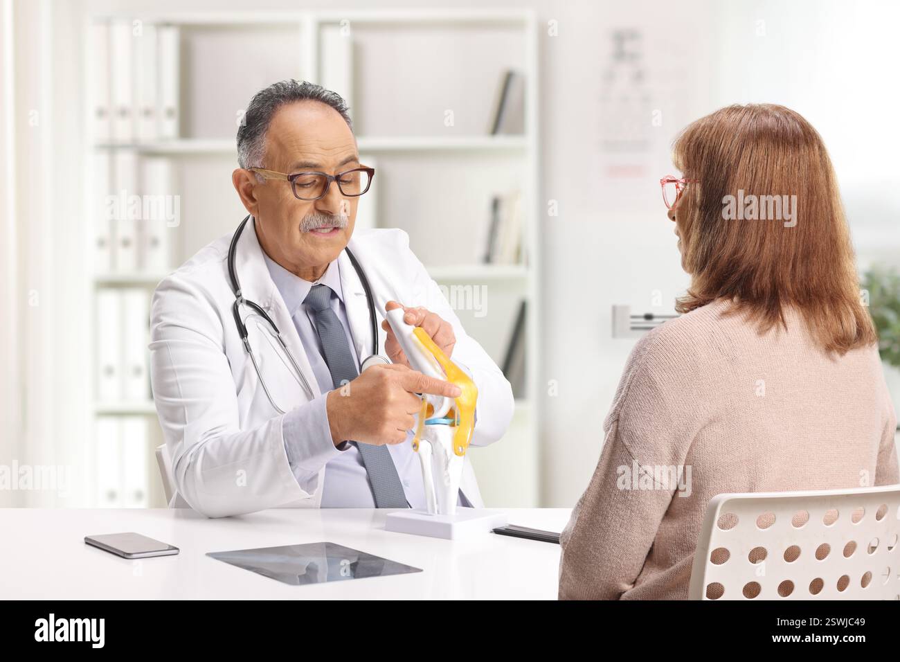 Doctor explaining a knee surgery procedure to a mature female patient ...