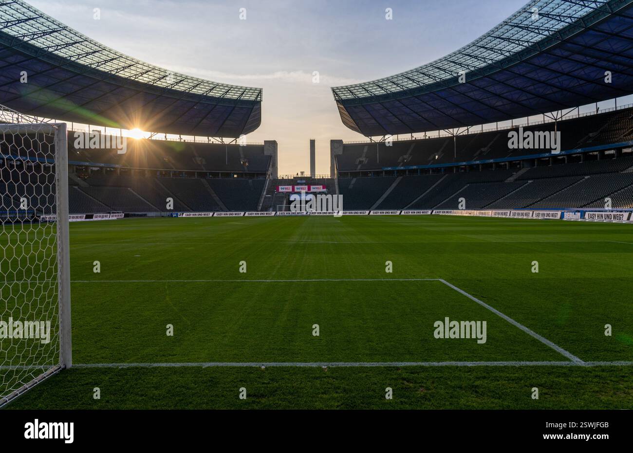 21 February 2025, Berlin: The setting sun shines through the gap ...