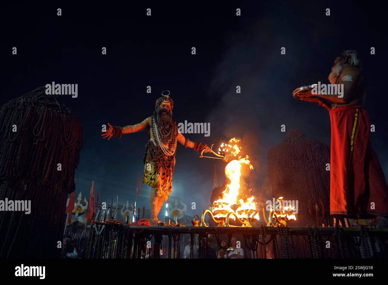 A Sadhu, or a Hindu holy man Mauni Baba rotates traditional oil lamps ...