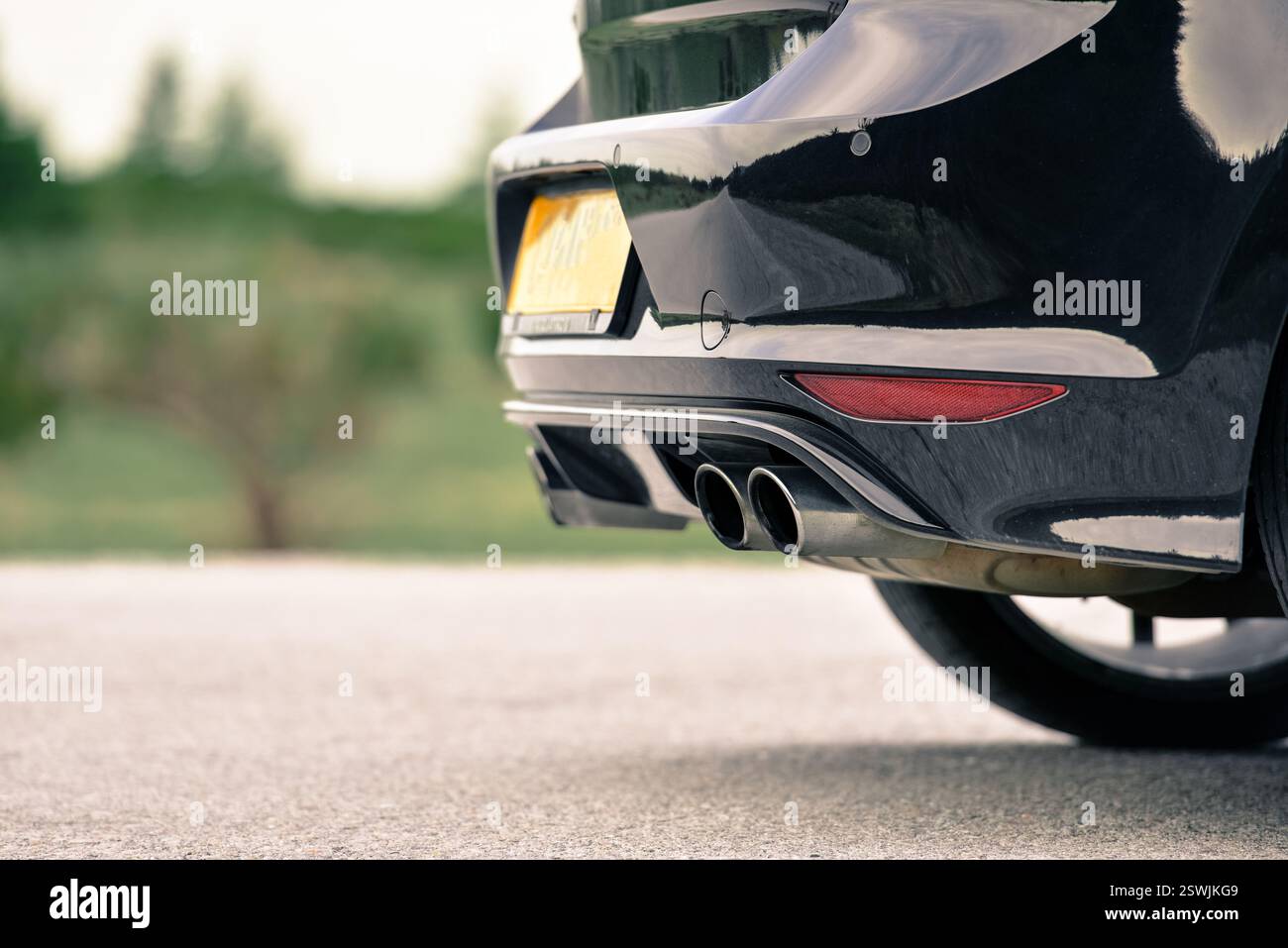 Close up of a black car's rear bumper and dual exhaust pipes The car is ...