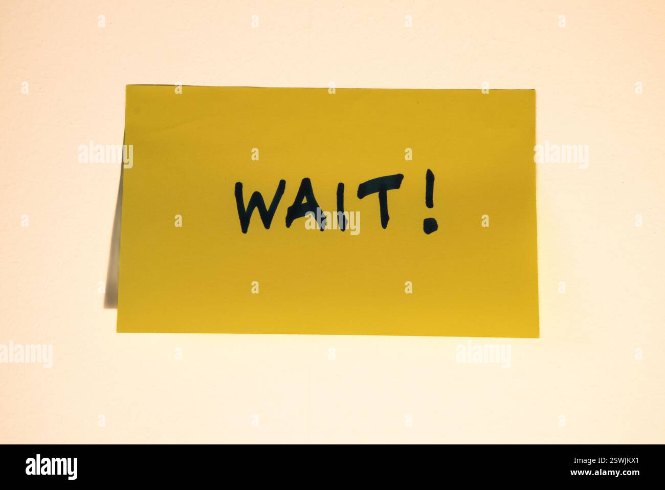 Wait, written on a yellow post It note Stock Photo - Alamy