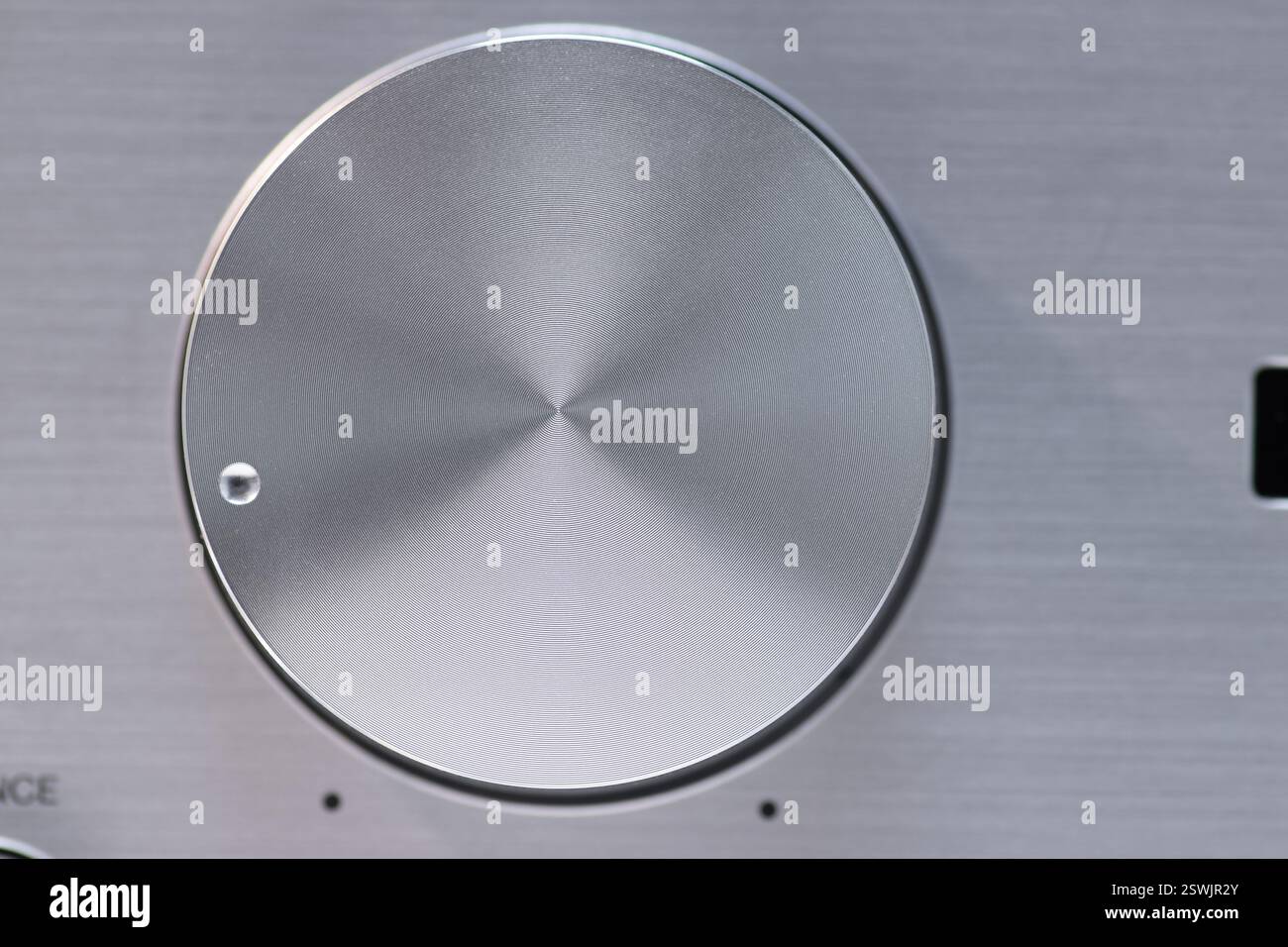 A macro view of a sleek silver volume control knob on an electronic ...