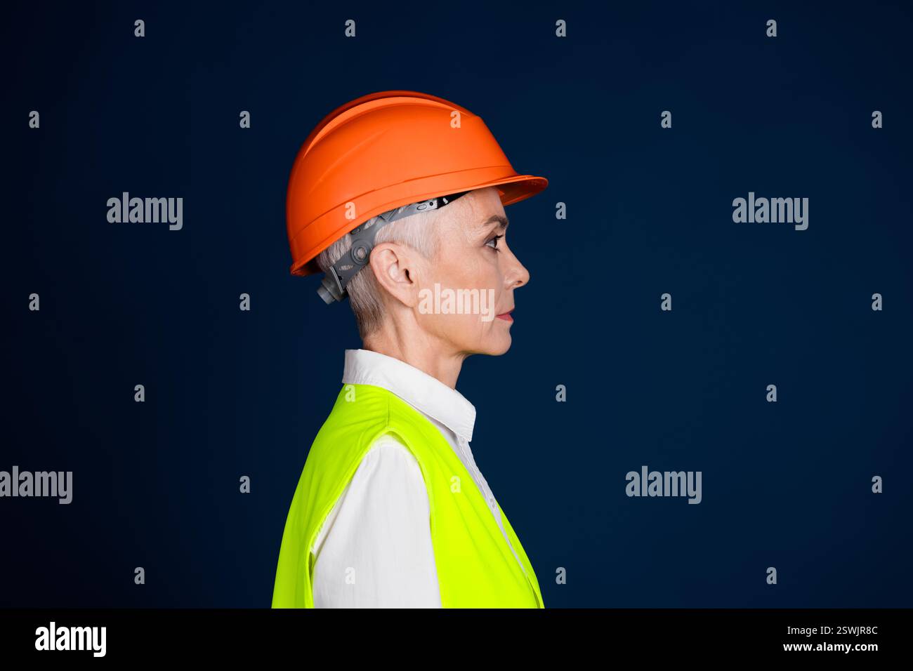 Profile of a mature female construction worker wearing a bright orange ...