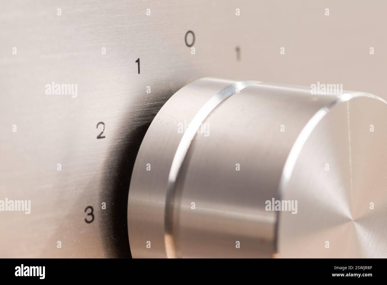 Detailed view of a shiny metal control knob on a device, with engraved markings for adjustable ...