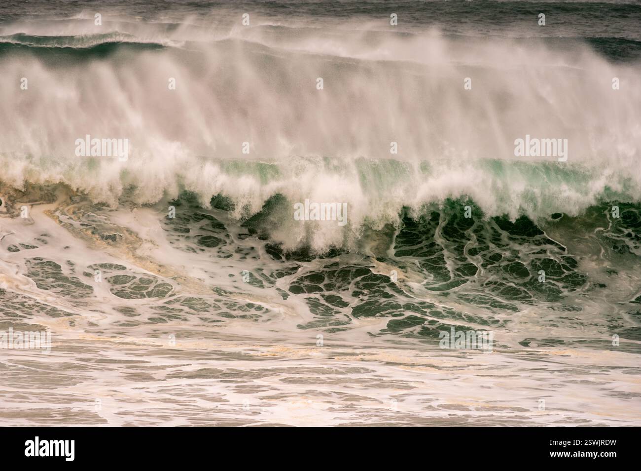 Powerful emerald waves crash with force, creating a dramatic scene of ocean energy and wild ...