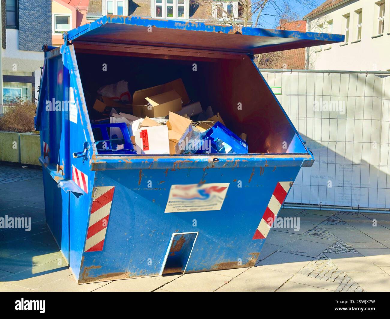 A blue waste paper recycling container with an open lid, revealing ...