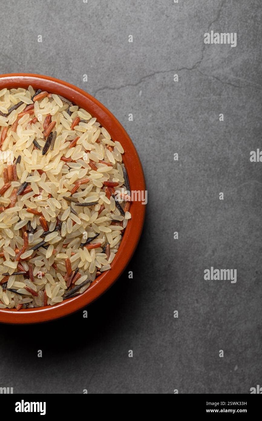 Earthenware bowl full of long, red, wild rice on a kitchen countertop ...