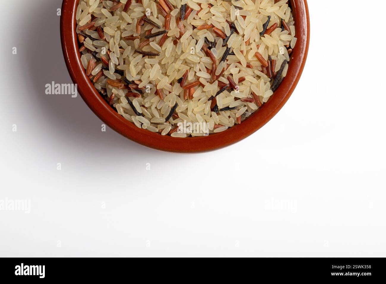 Earthenware bowl full of long, red, wild rice on a kitchen countertop ...