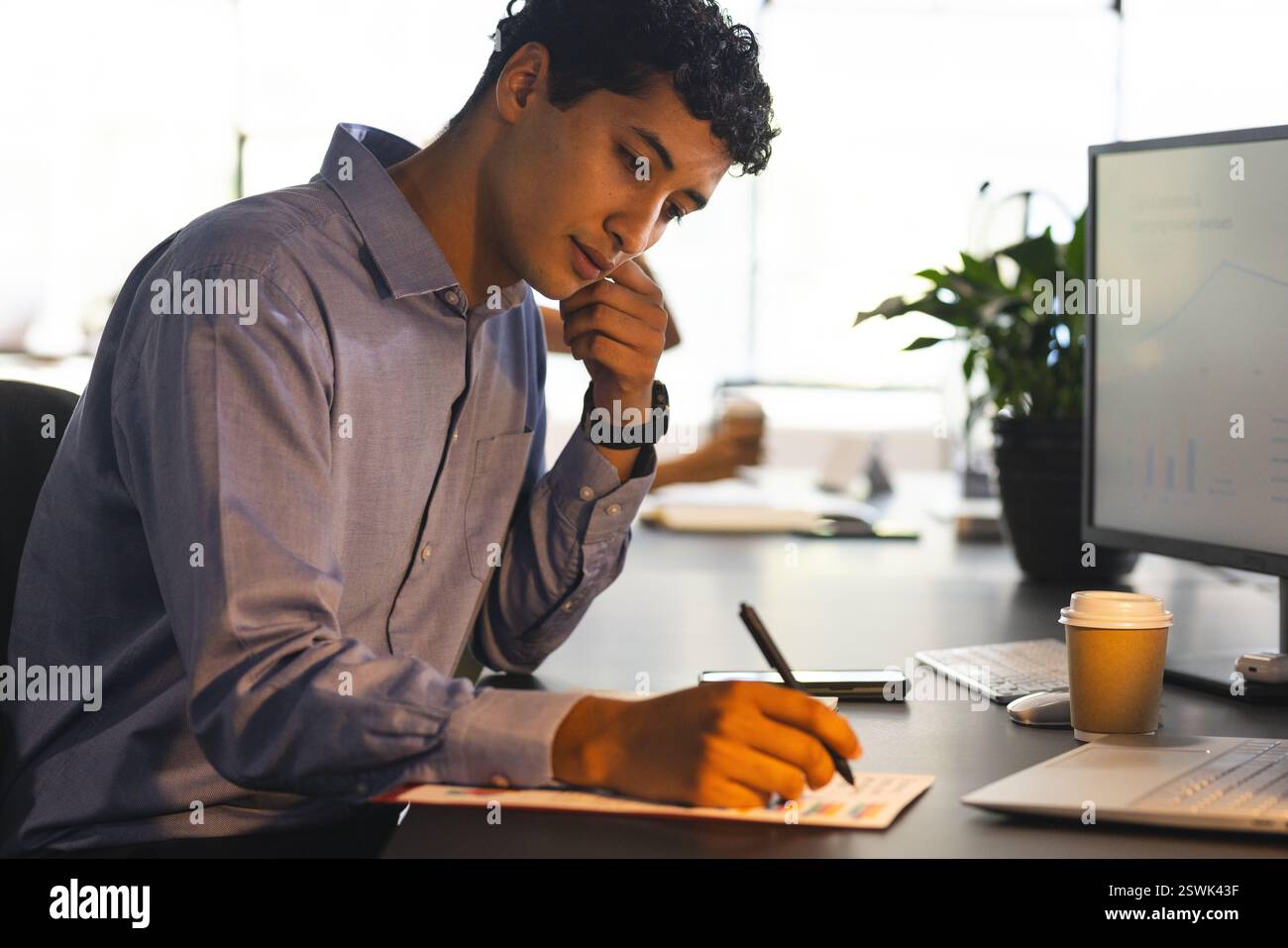Business professional analyzing documents at office desk with coffee ...