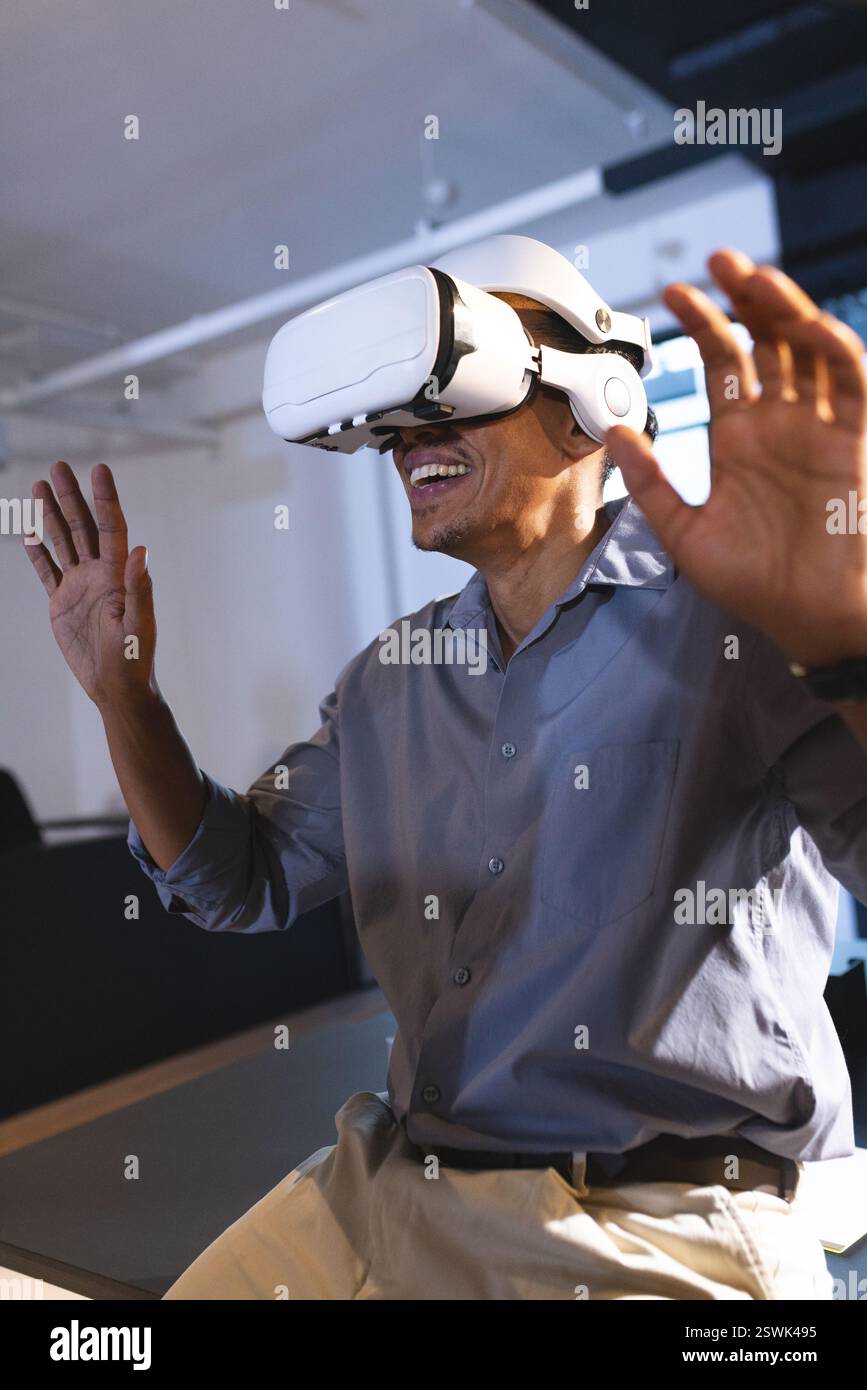 In office, man using VR headset, smiling and interacting with virtual ...