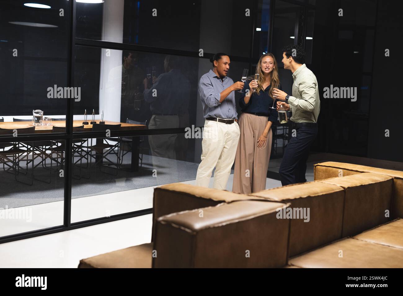 Diverse colleagues in office celebrating success with drinks, enjoying ...