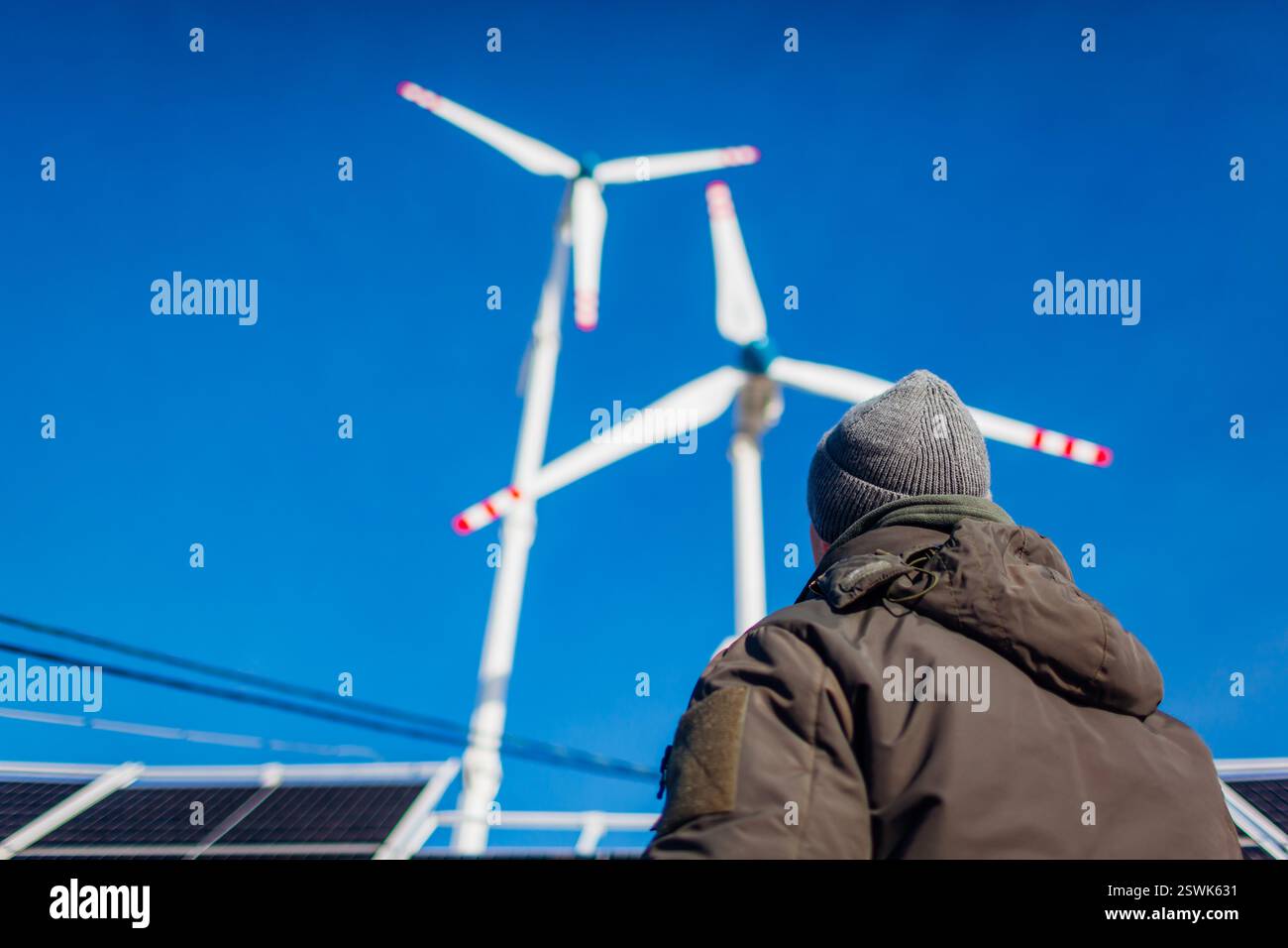 Worker checking solar energy panel and wind turbines power generator ...