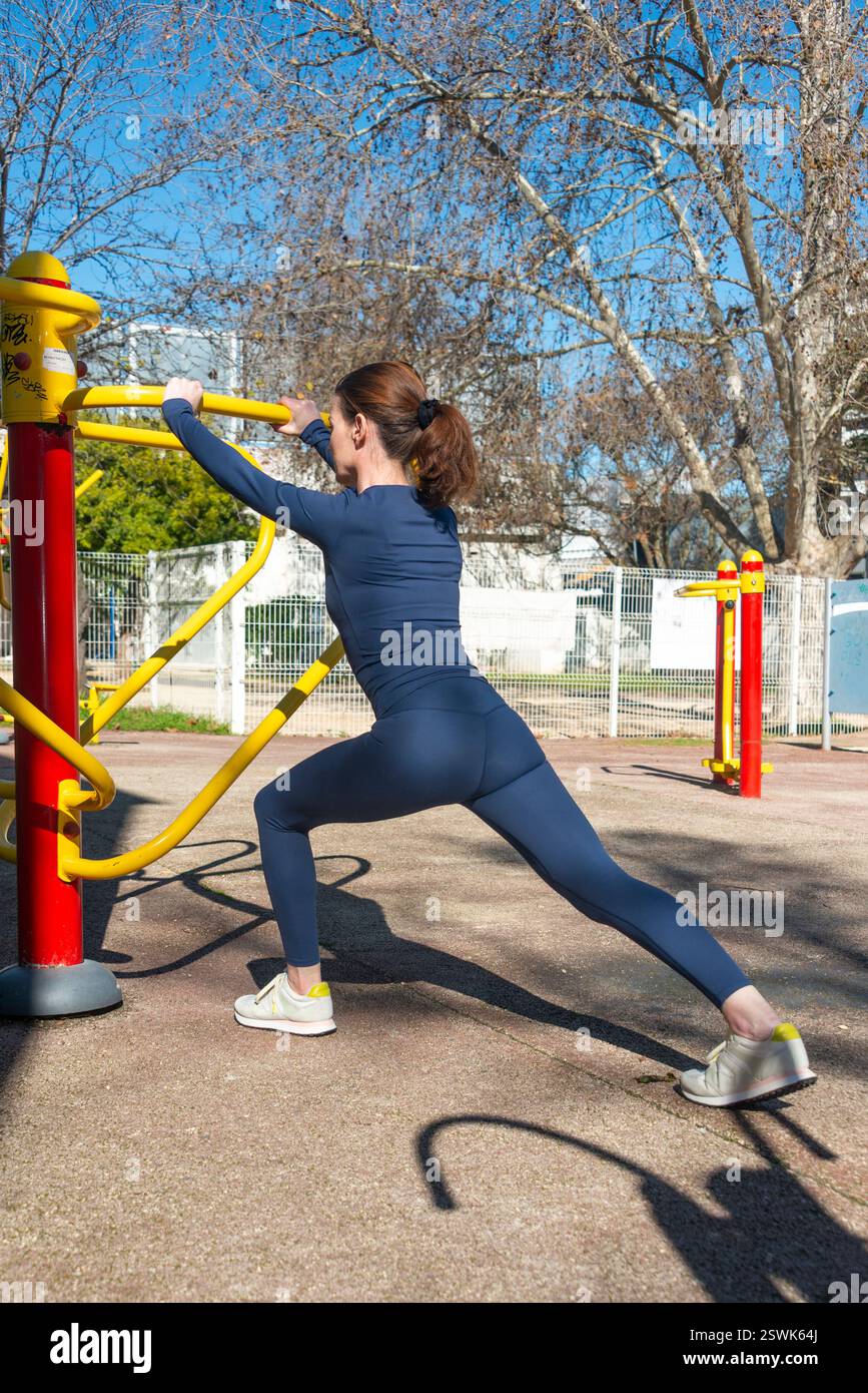 woman working out at an outdoor gym, doing a leg stretch exercise Stock ...