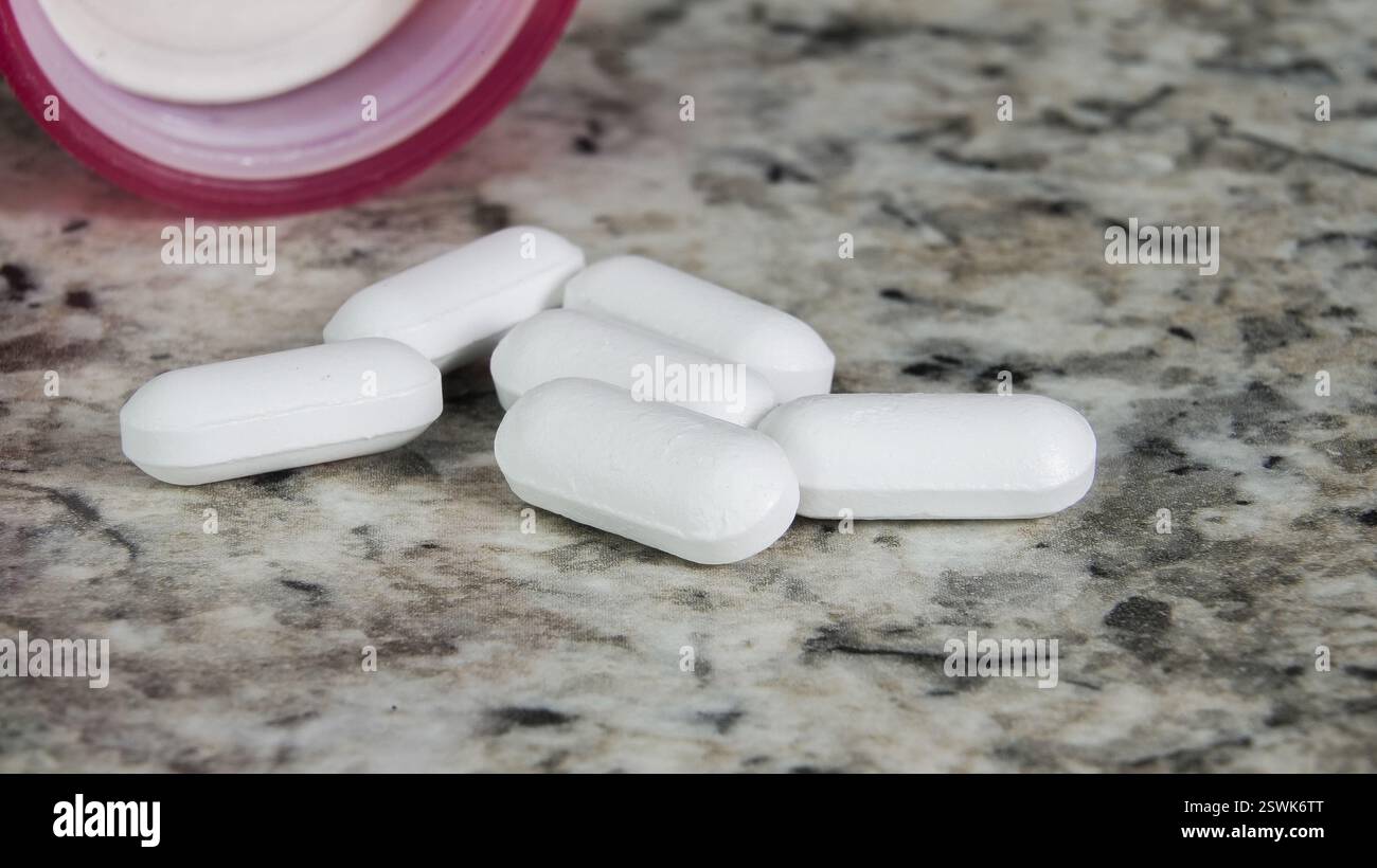 Six white tablets are scattered on a granite countertop beside an open ...
