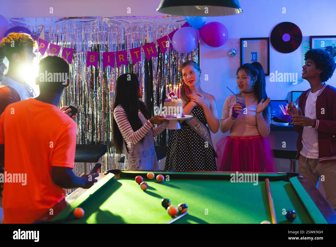 Diverse teen friends celebrating birthday with cake and drinks around ...