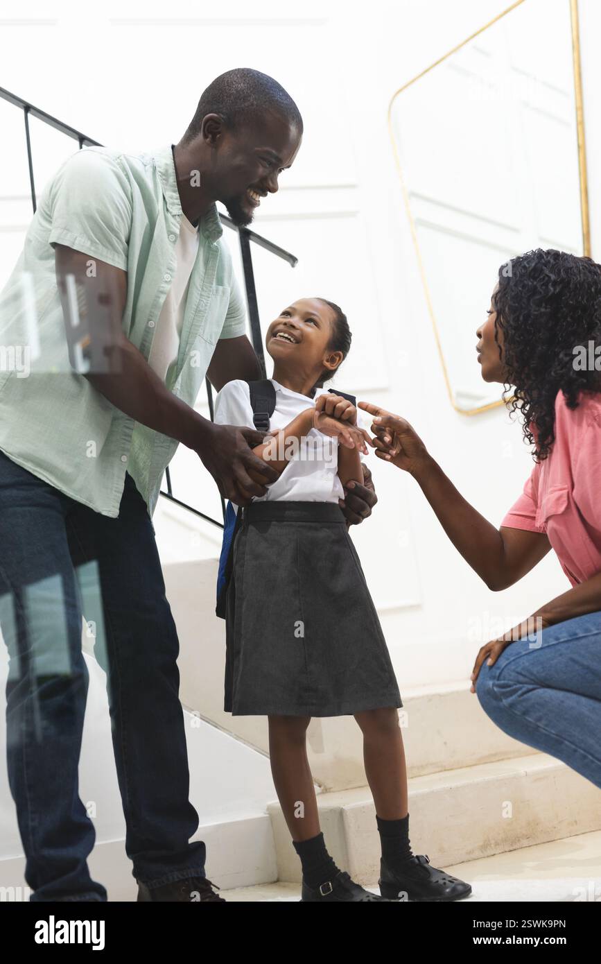 Diverse father and diverse mother encouraging daughter in school ...