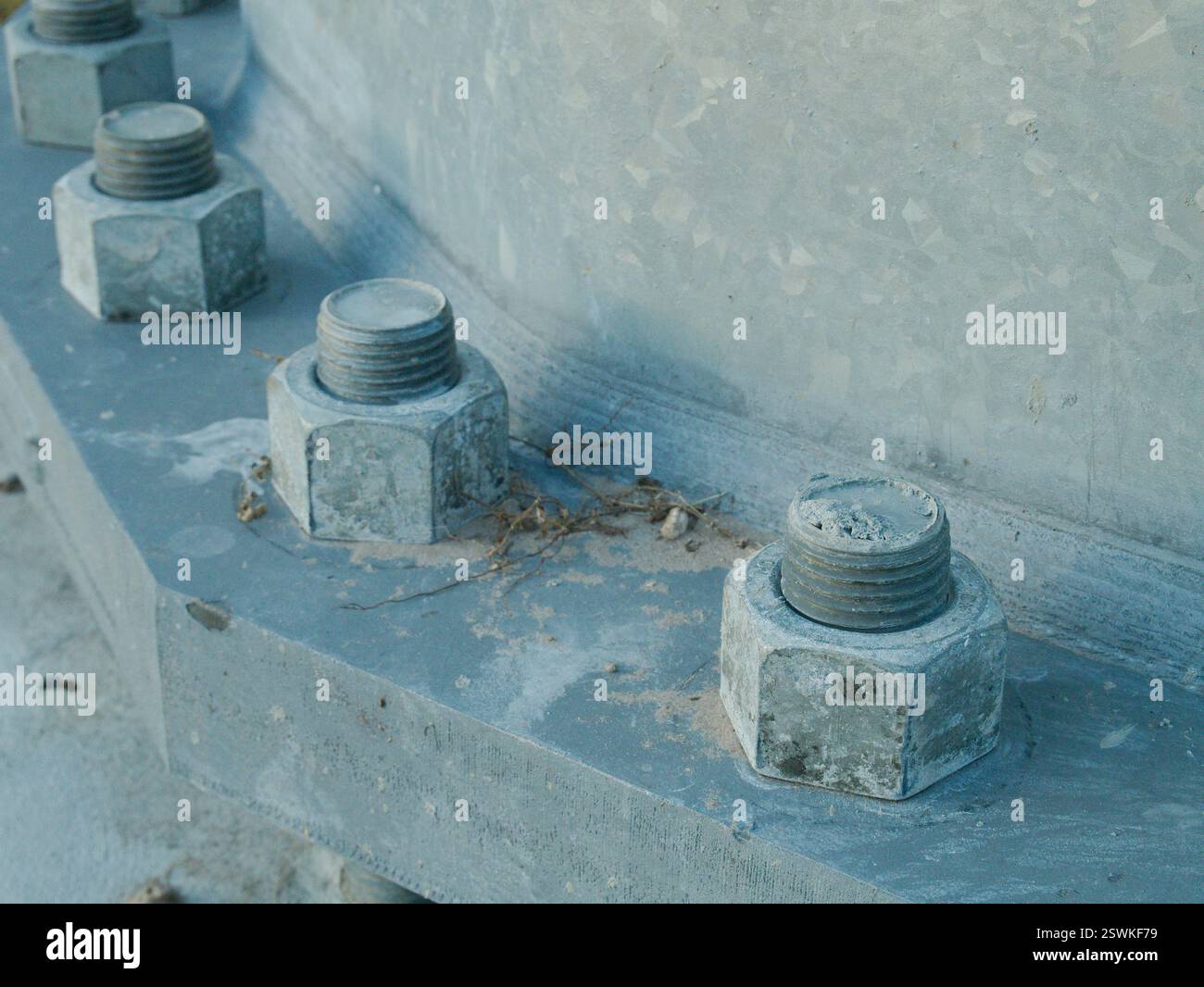 Wide close up view of four large bolts and nuts near sunset of the base ...