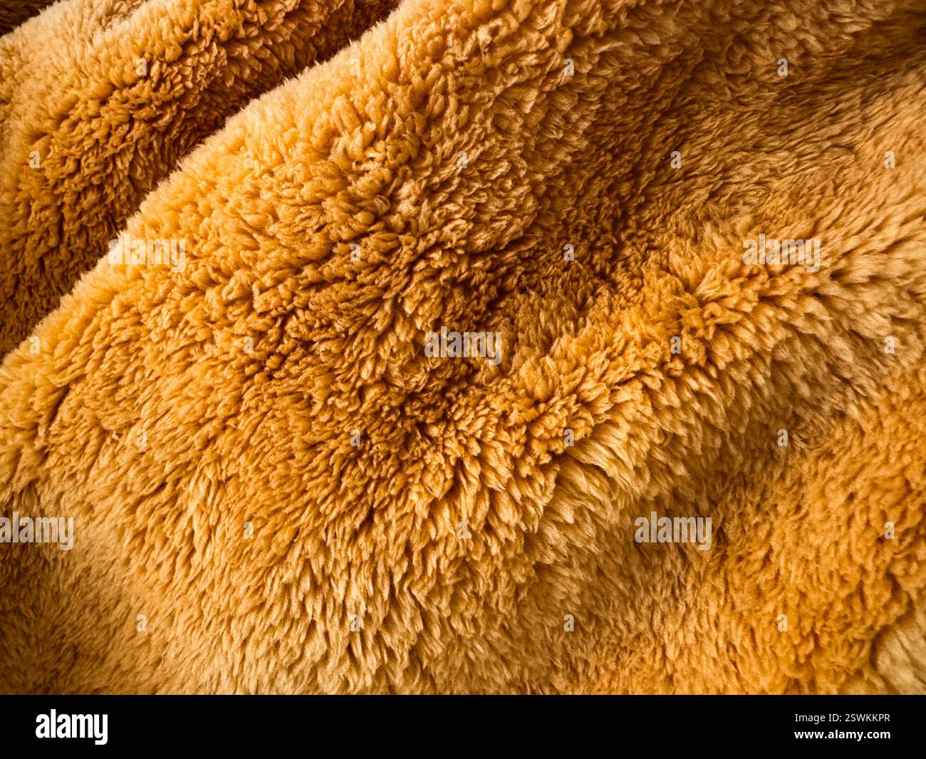 A warm, textured fabric displays a blend of soft fibers in golden brown ...