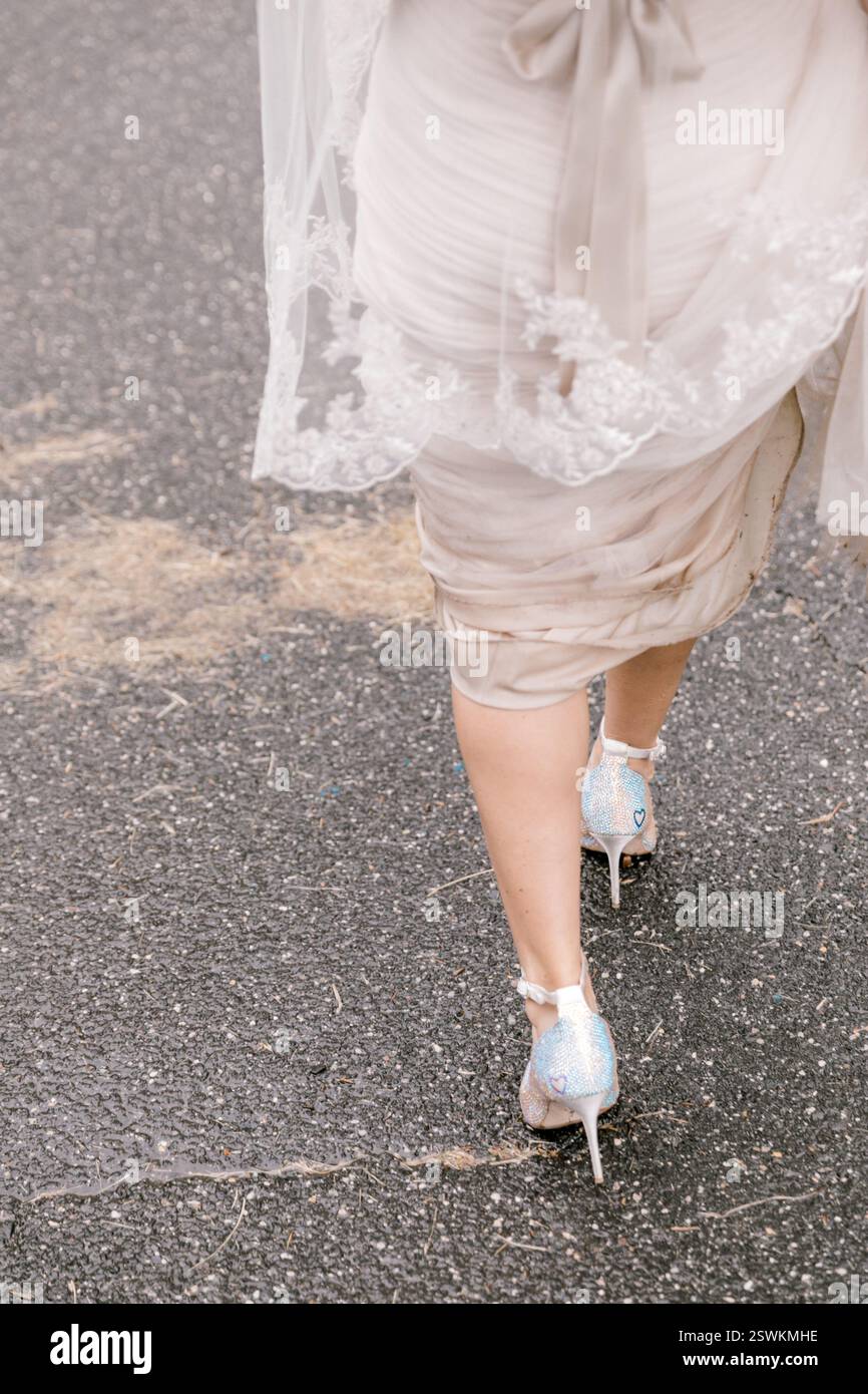 A bride in a stunning gown strides confidently down a rustic road in ...