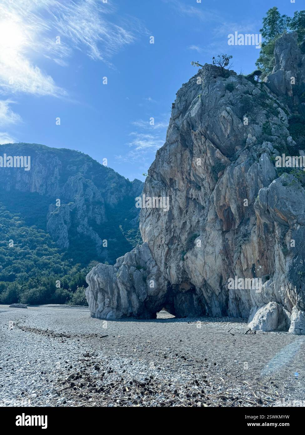 A stunning rock formation stands tall by the coast, surrounded by ...