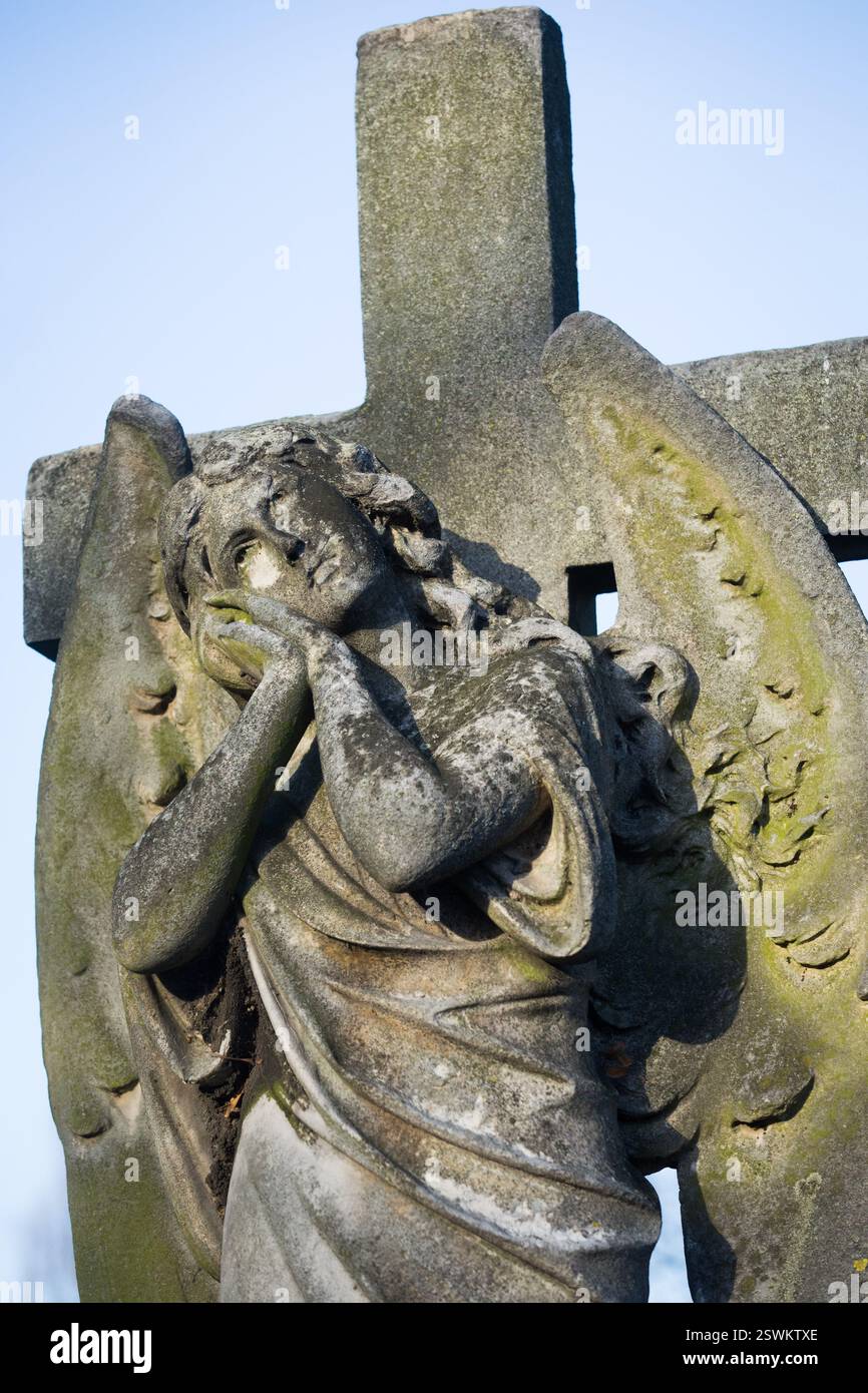 Weeping angel statue, weathered stone cross, Brompton Cemetery, London ...