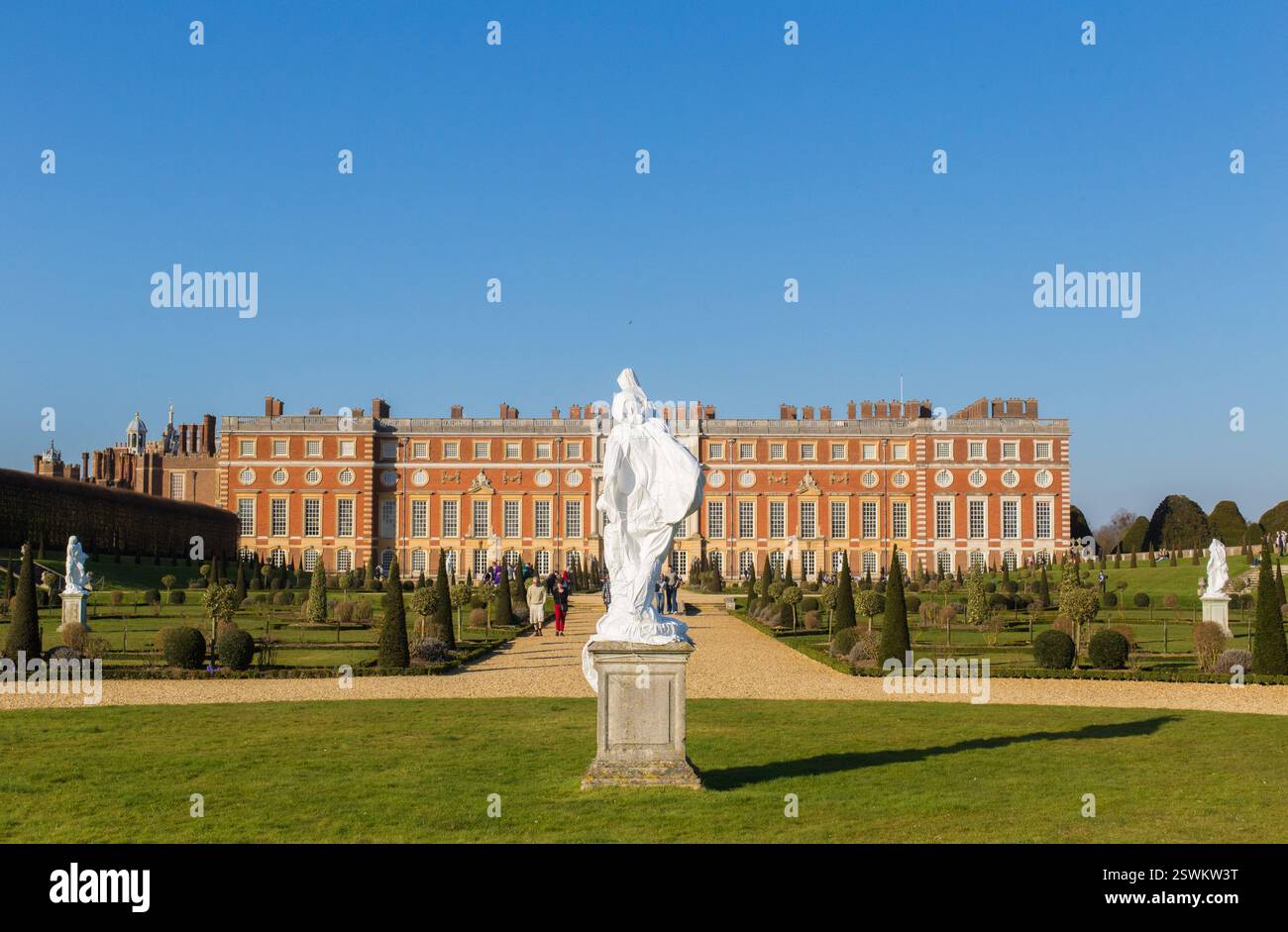 Visitors at Hampton Court Palace gardens, observe a covered statue. The ...