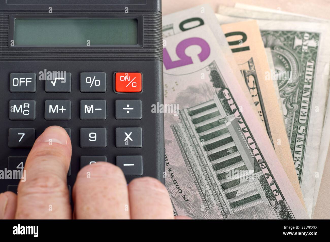 Closeup person's hand using calculator counting american dollar bills ...