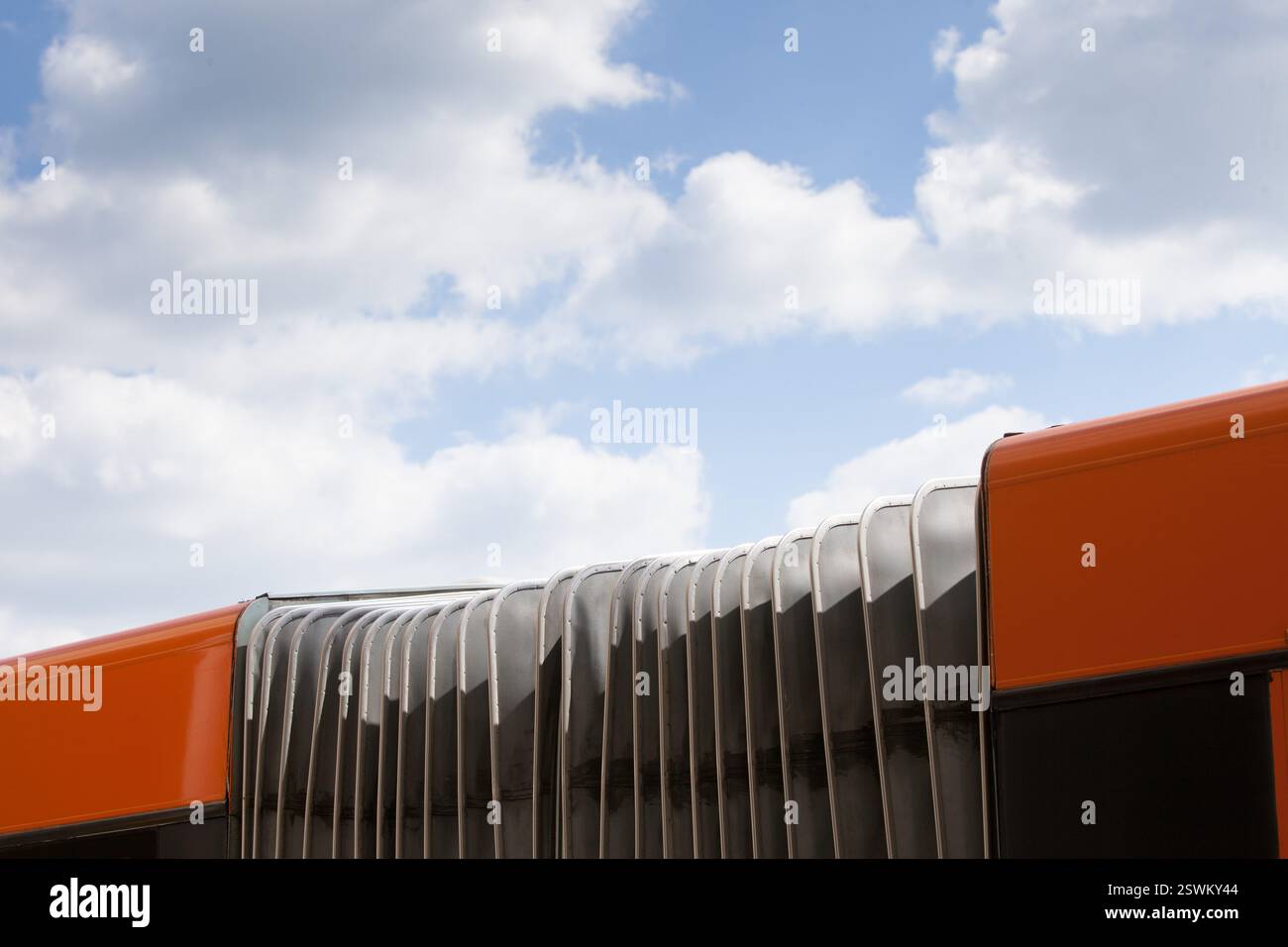 Orange and black bus, likely a transit vehicle, with a series of metal ...