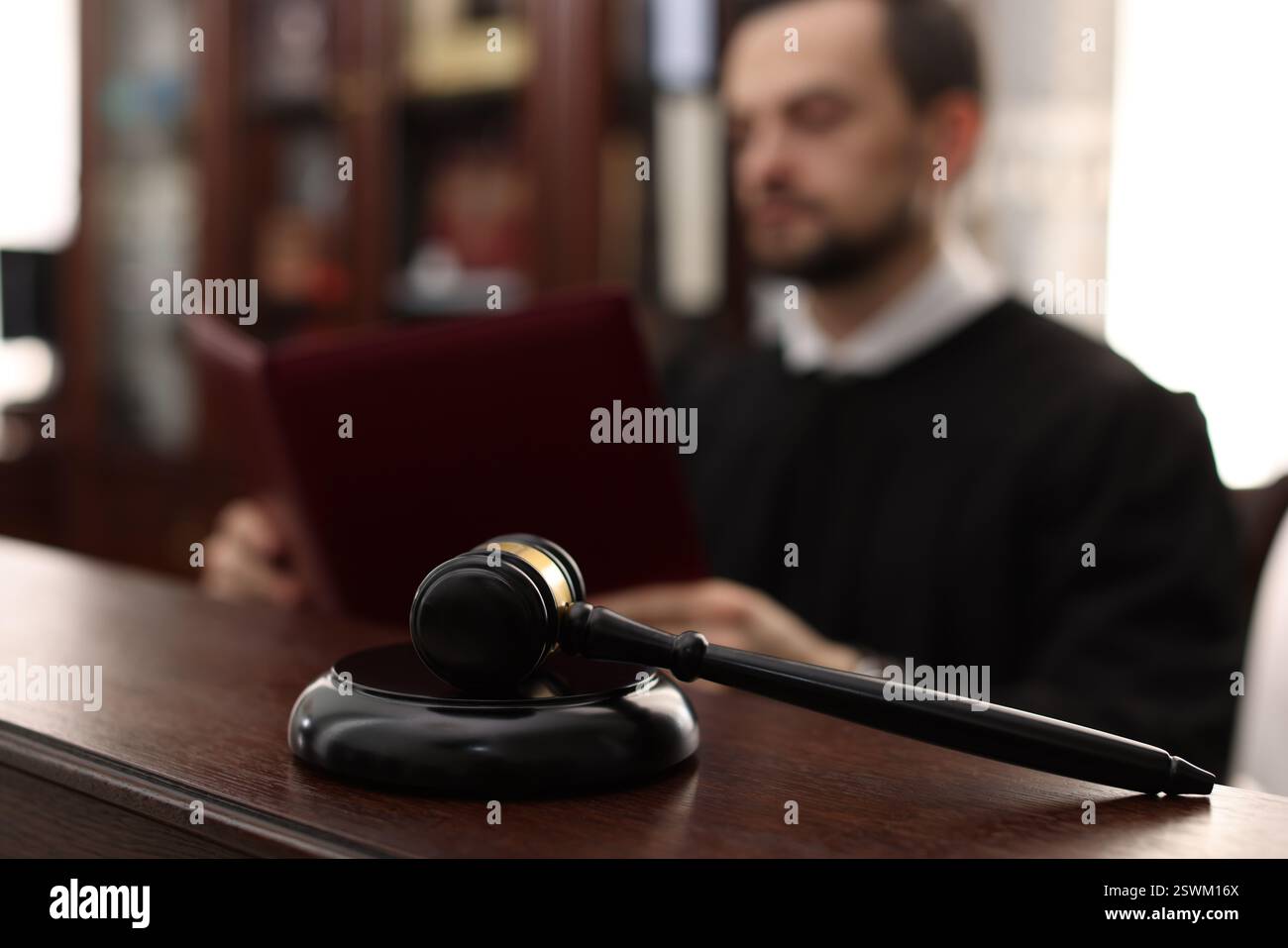 Judge with folder of documents at wooden table in courtroom, focus on ...