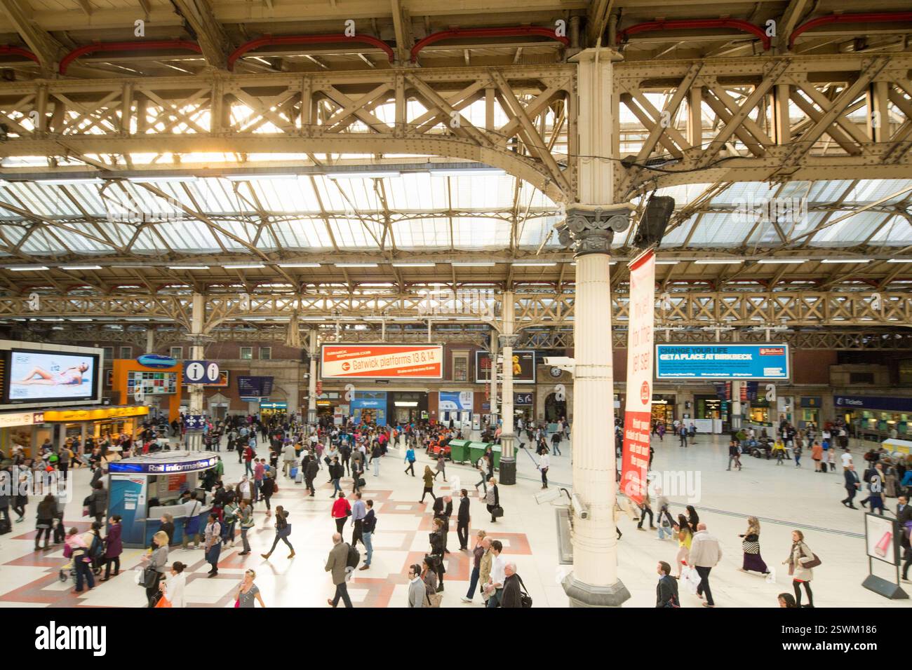 Crowded interior of London's Victoria station. People navigate the ...