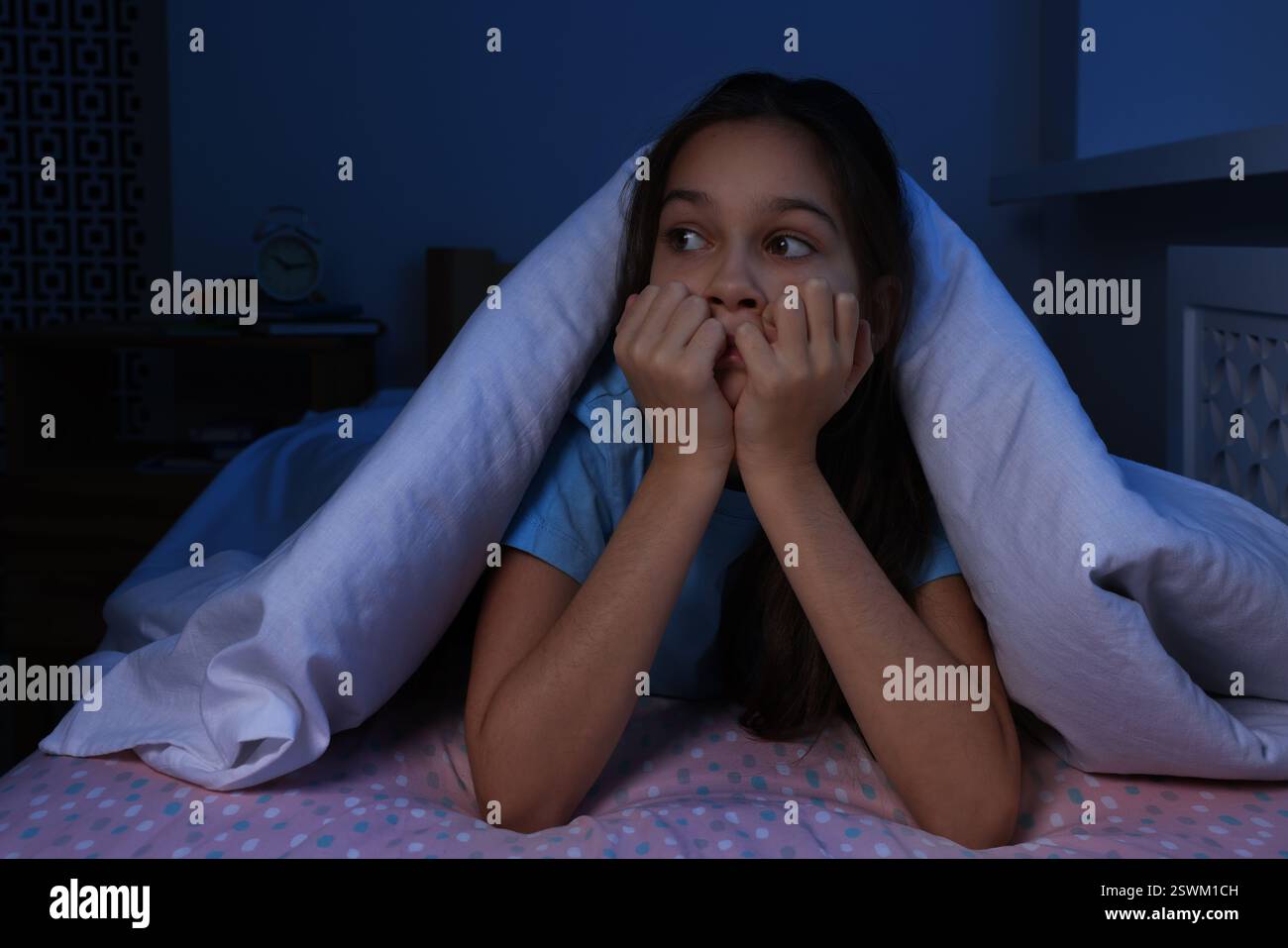 Afraid girl hiding under duvet on bed at night Stock Photo - Alamy