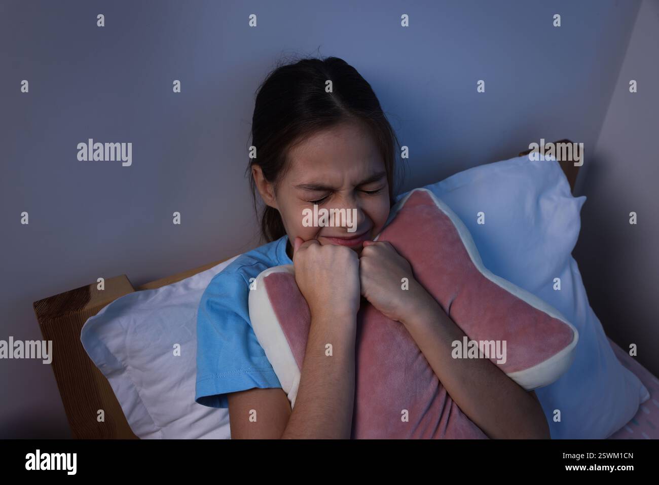 Afraid girl with pillow in bed at night Stock Photo - Alamy